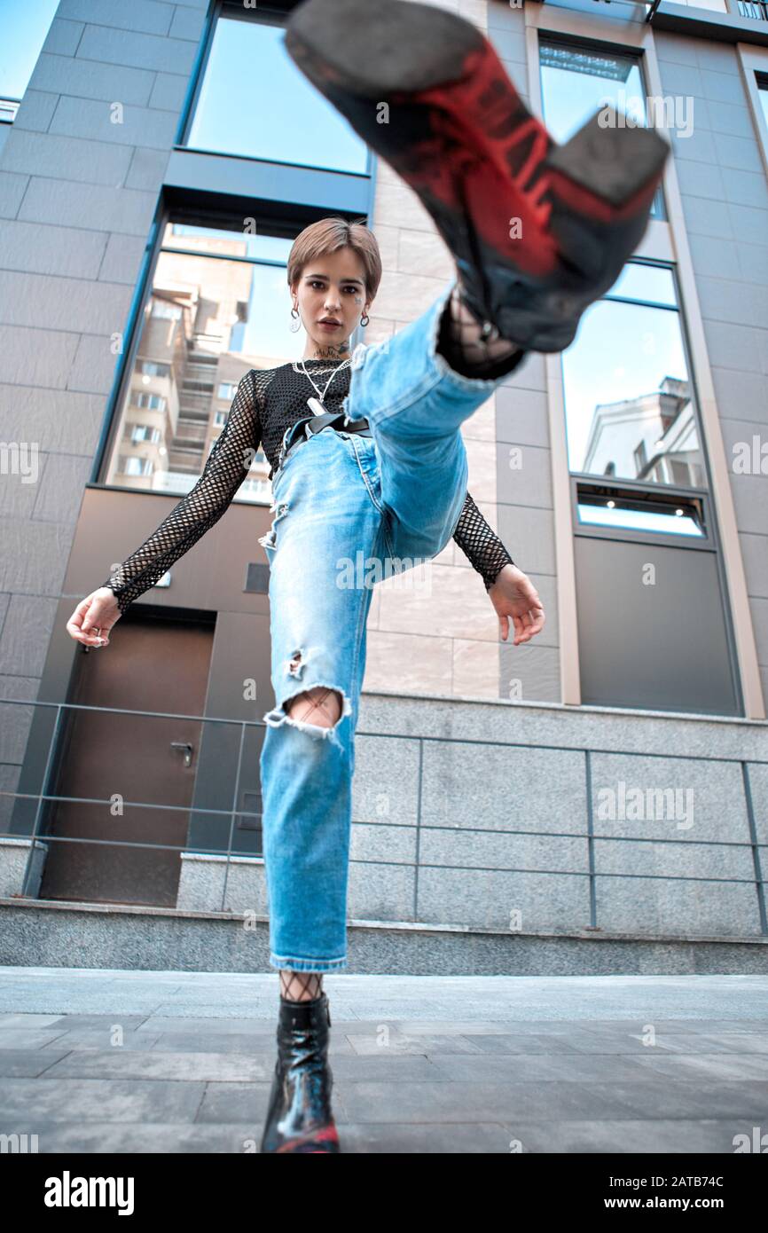 Urban Style. Young stylish woman standing leg up in kick near ...