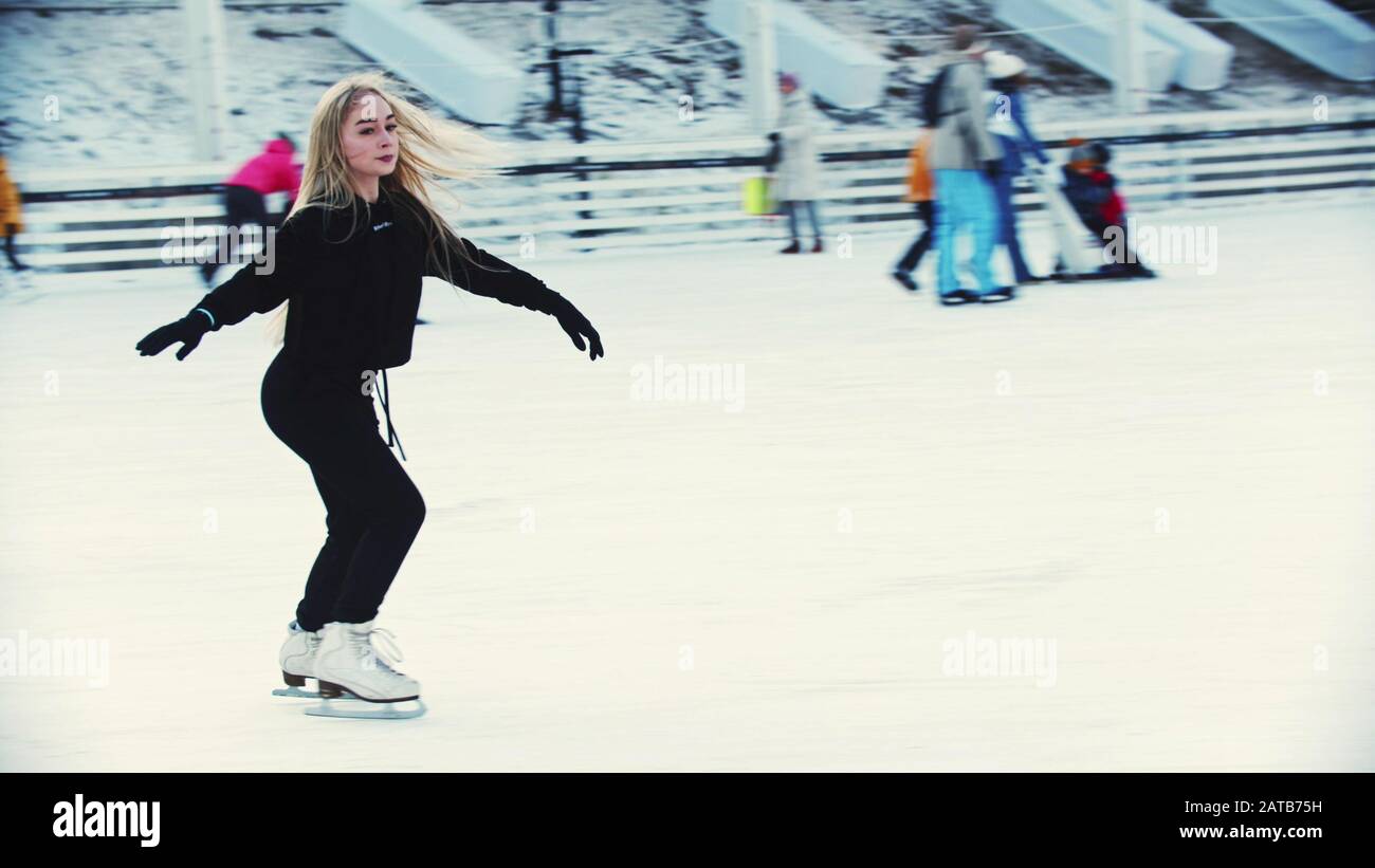 A young woman figure skater skating on the ice rink around people Stock ...