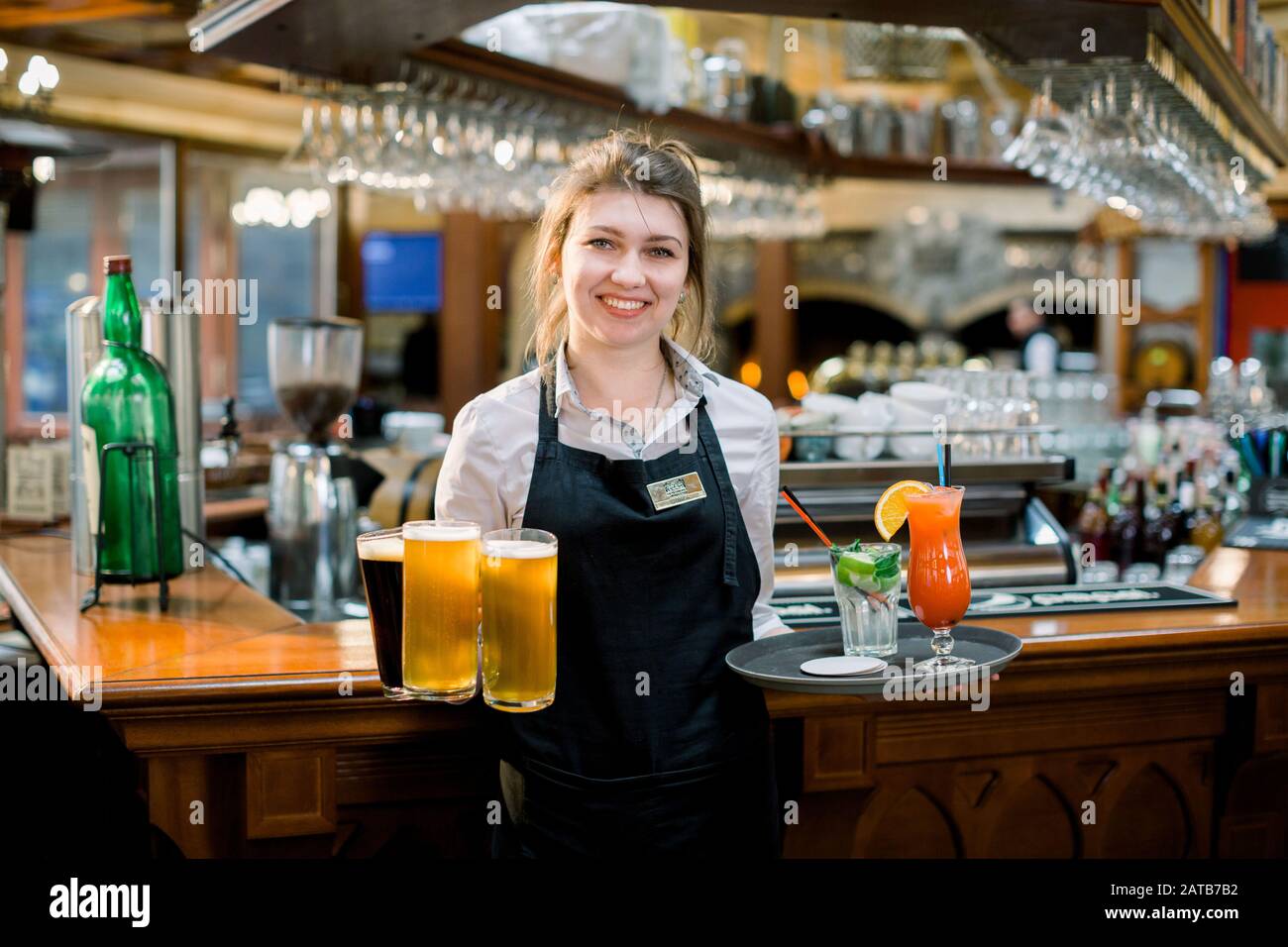 Smiling friendly waitress serving a pint of draft beer in a pub ...