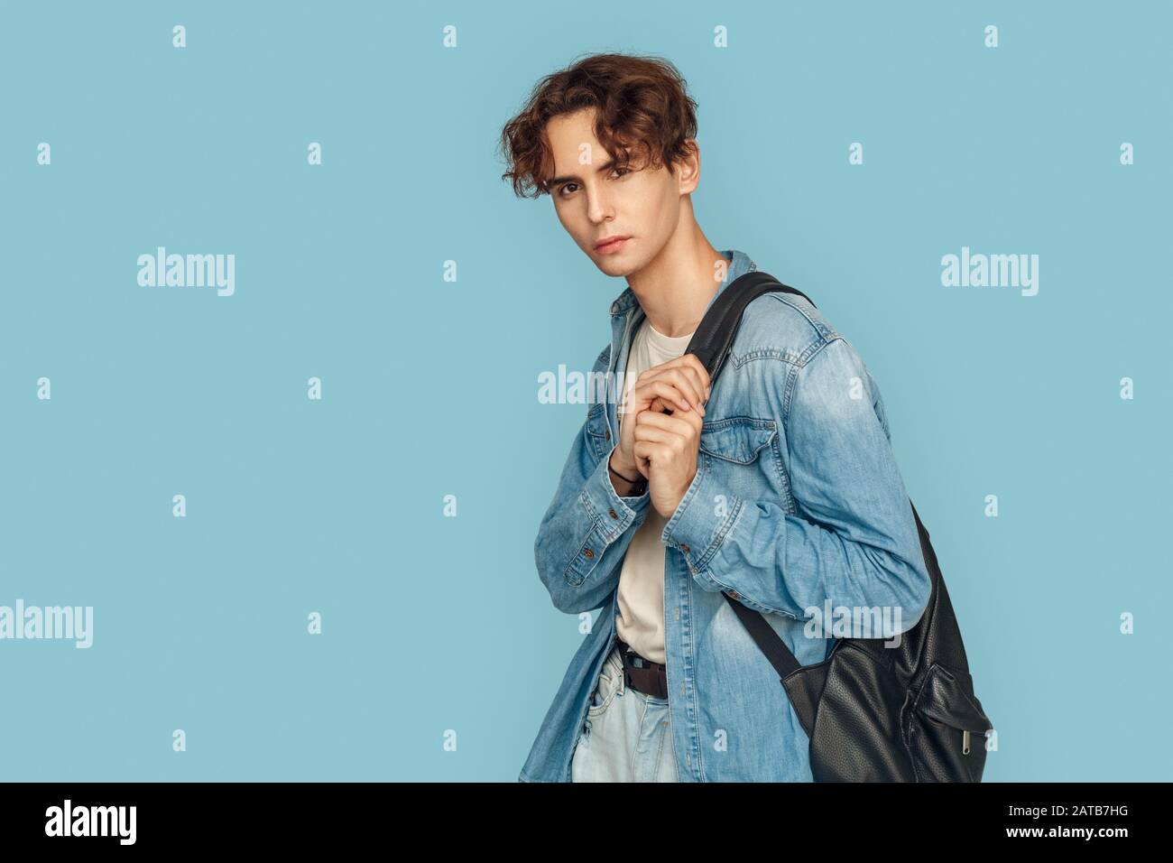 Freestyle. Man in denim shirt with backpack standing isolated on gray ...