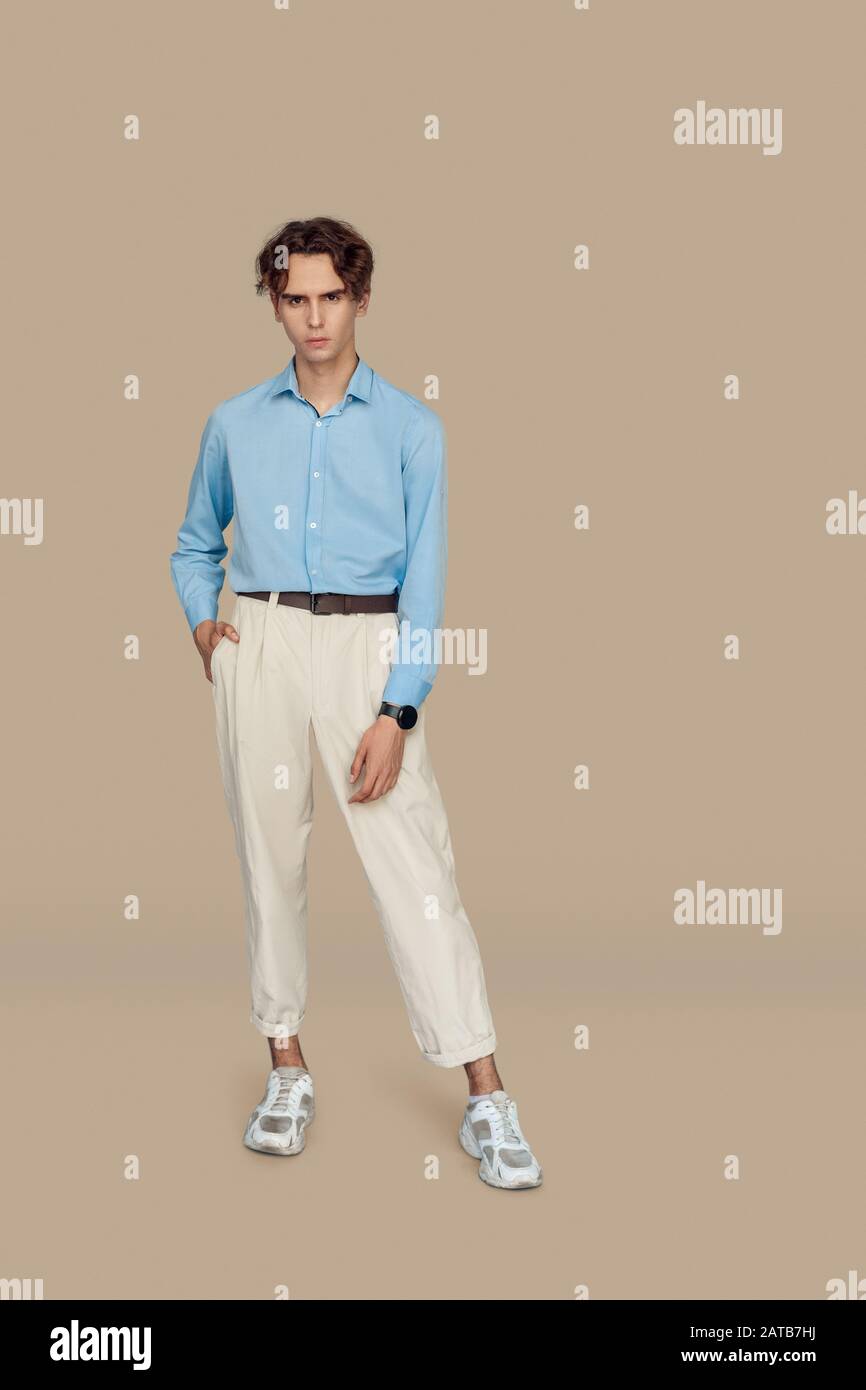 Freestyle. Man in formal wear standing isolated on gray posing serious ...