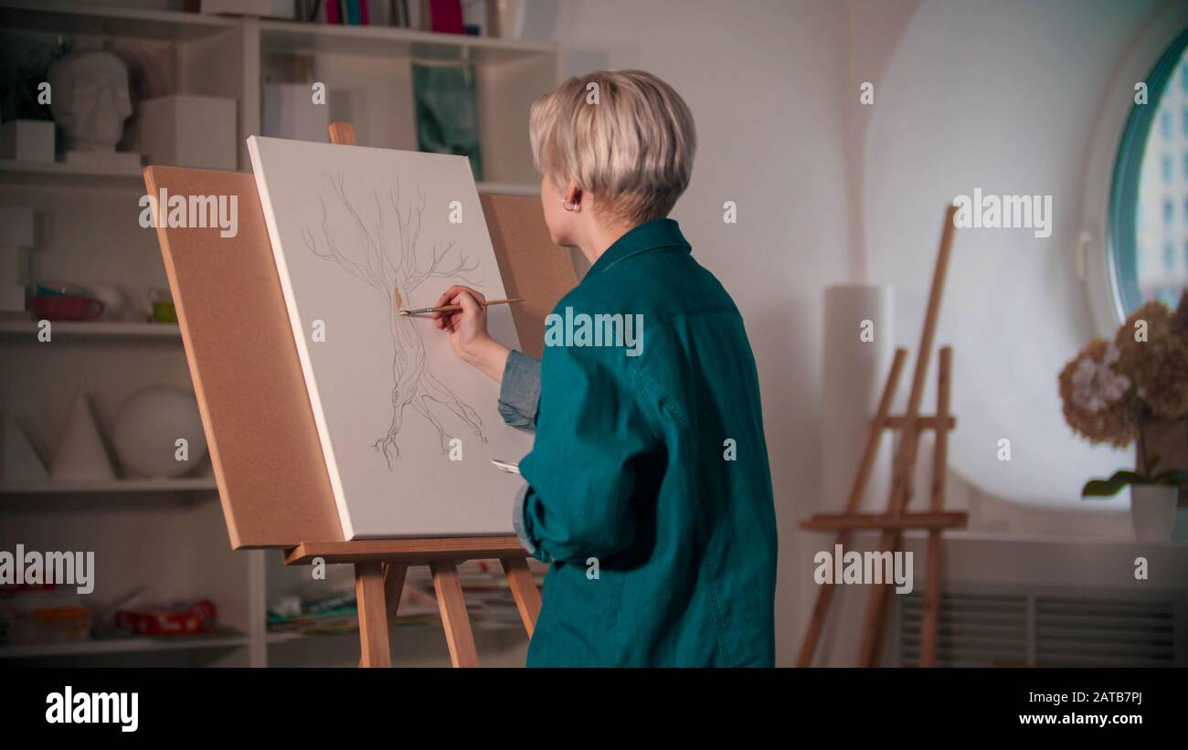 A young woman artist coloring her painting of the tree Stock Photo - Alamy