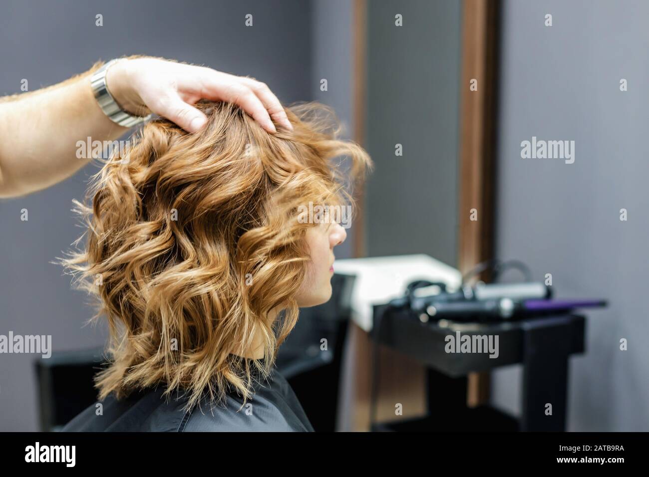 Female hairdresser checking woman's hairstyle in beauty salon, close up ...