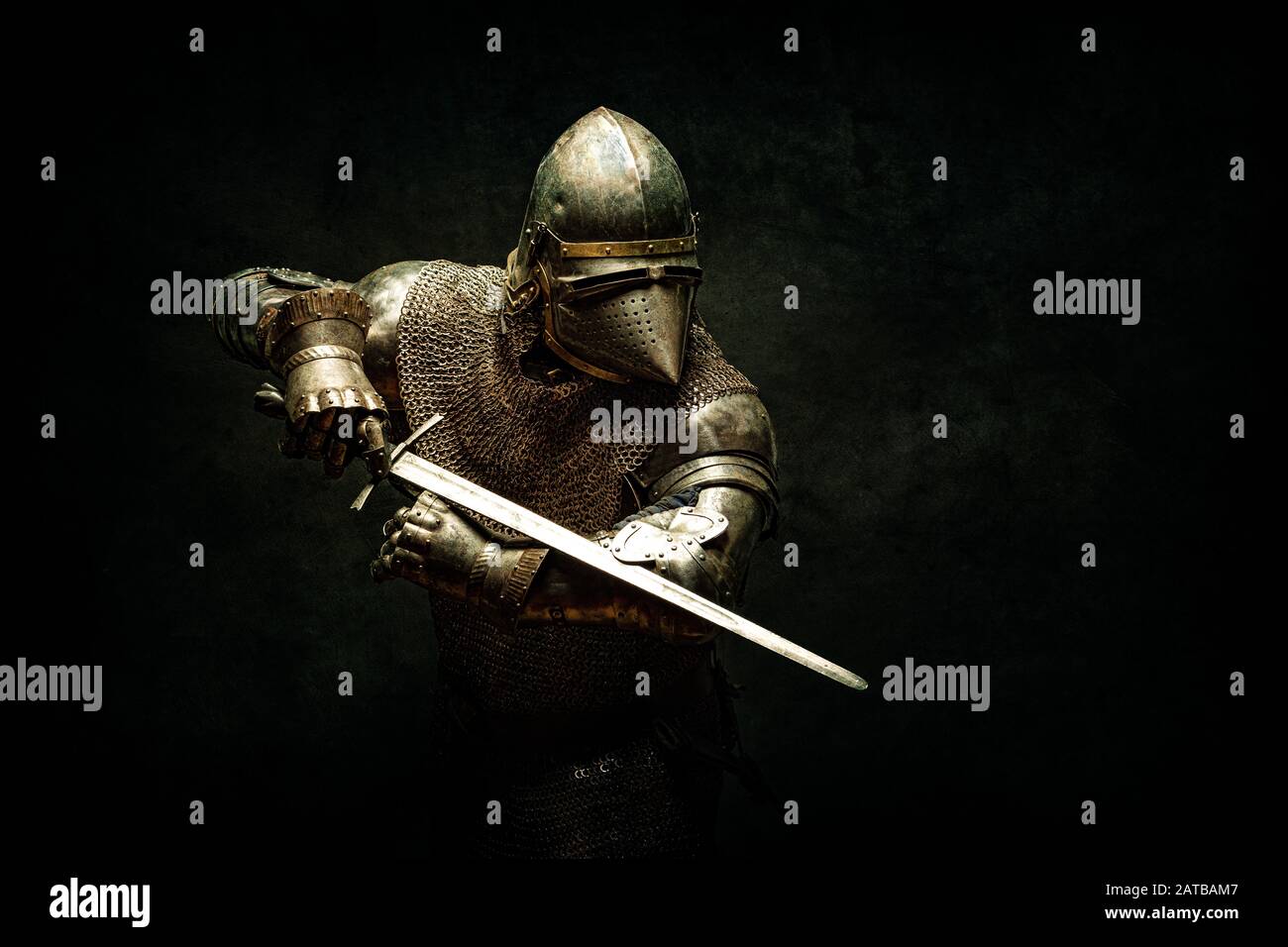 Portrait of a knight in armor, his sword in his hands, performing an ...