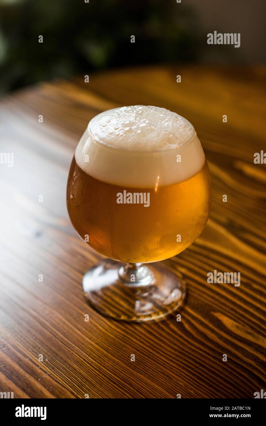 Frothy globe glass of craft beer Stock Photo - Alamy