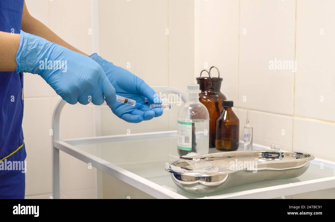 The doctor prepares a syringe with an injection and saline solution ...