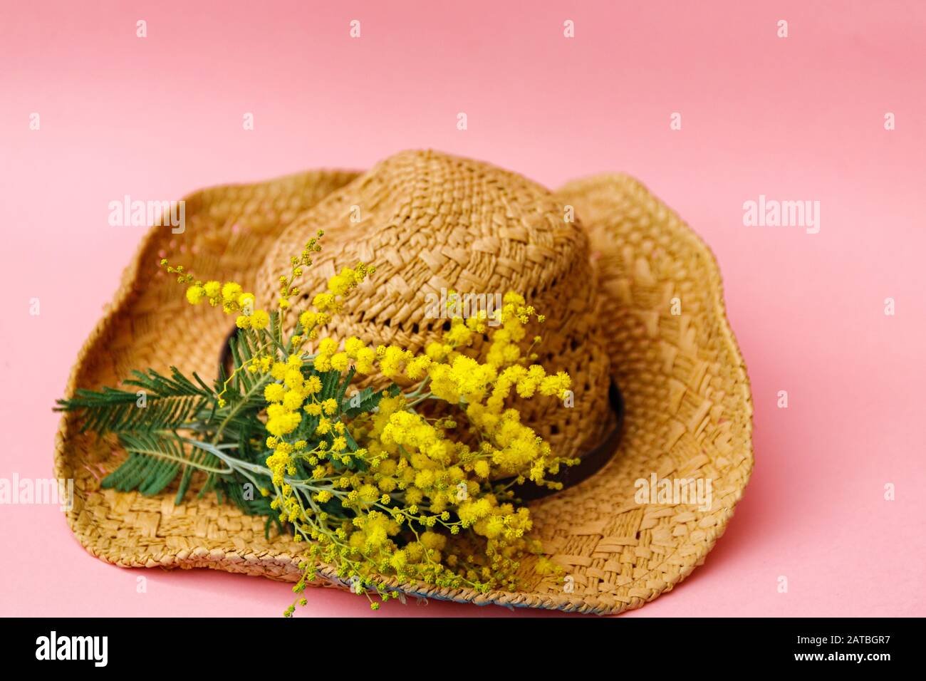 spring straw hat with mimosa on pink background Stock Photo - Alamy