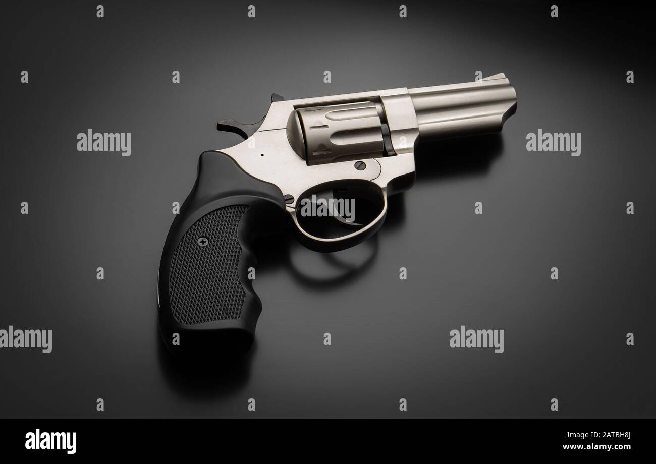 Silver pistol revolver on a black background. Low key photography ...