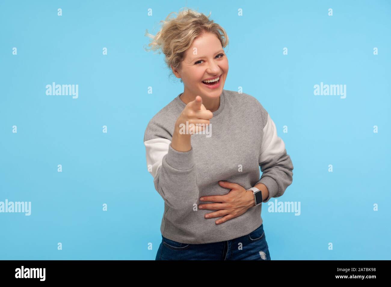 Joyful happy woman with short curly hair in sweatshirt pointing at ...