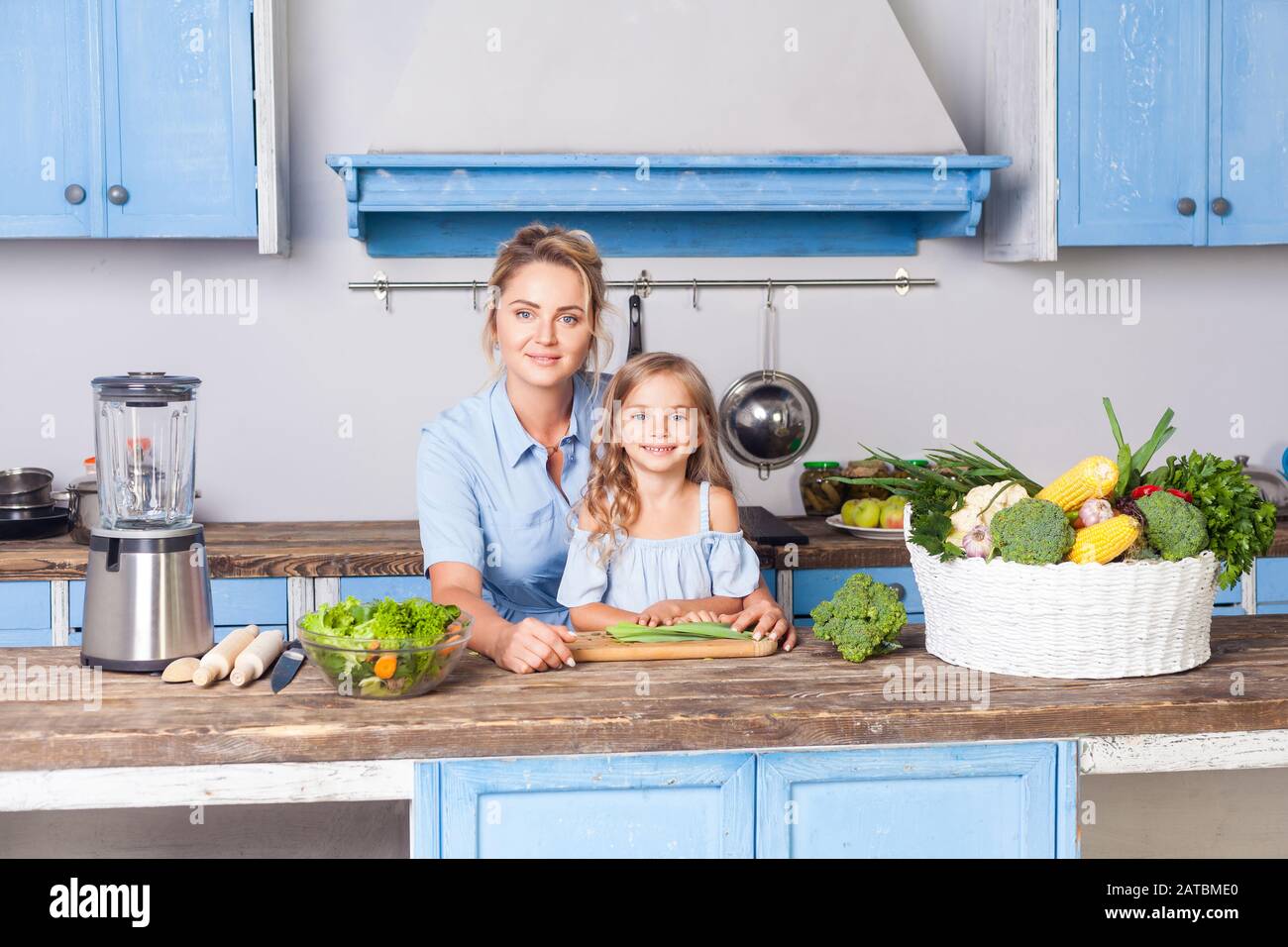 Young woman and lovely girl sitting in modern kitchen, looking at ...
