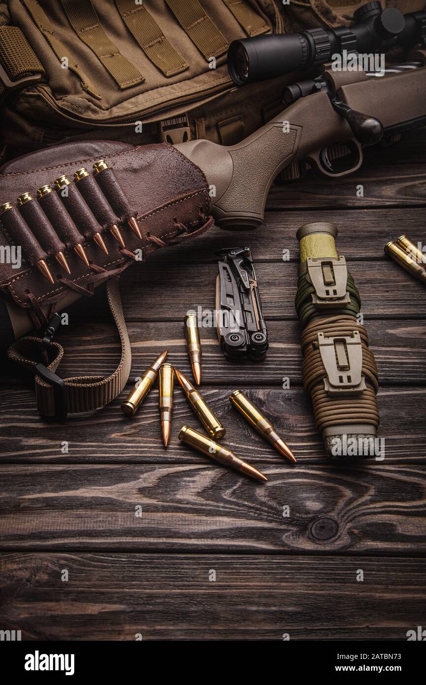 Modern bolted carbine and cartridges for it on a dark wooden table ...