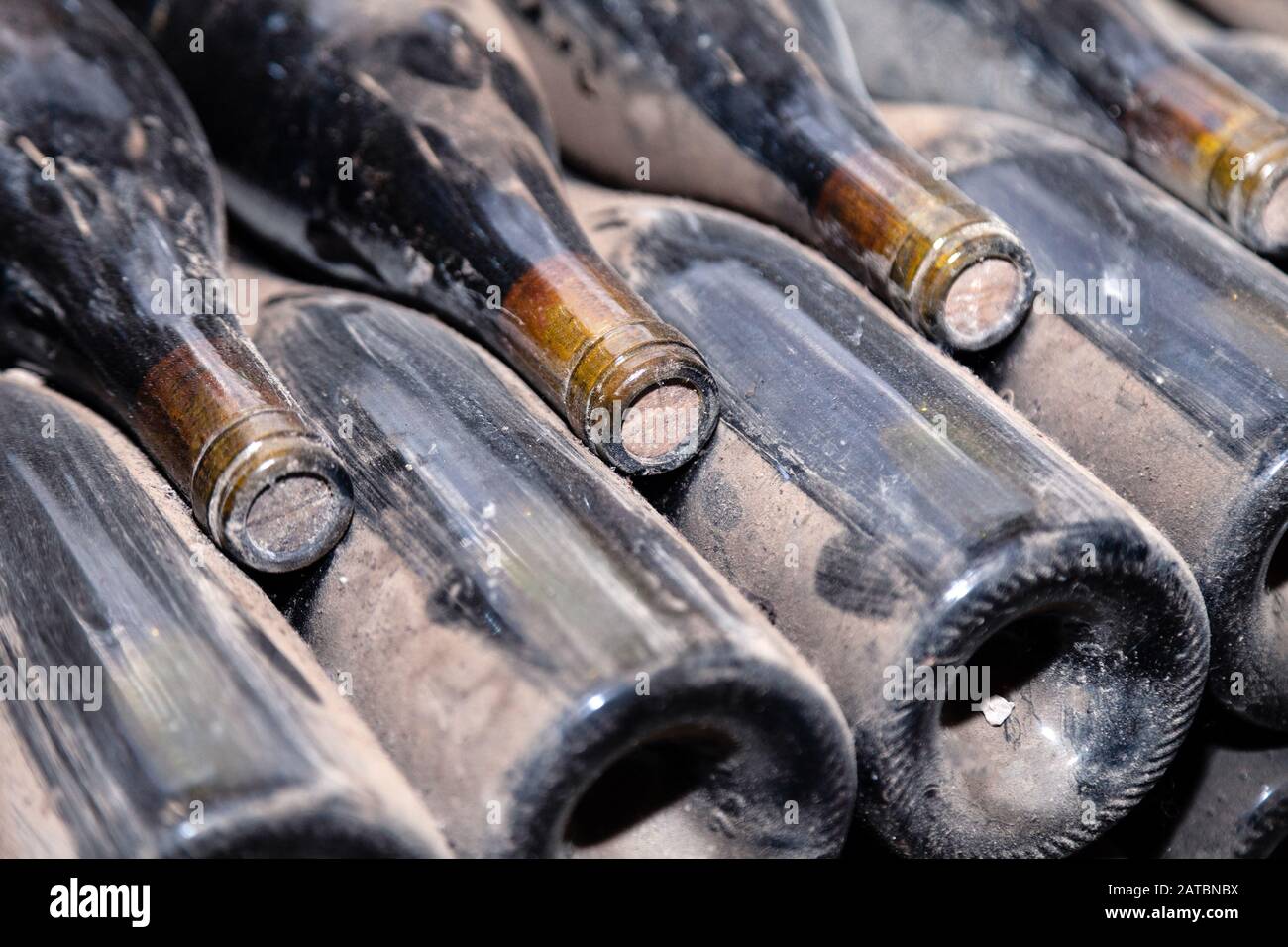 Ancient dark dusty wine bottles aging in underground cellar in rows ...