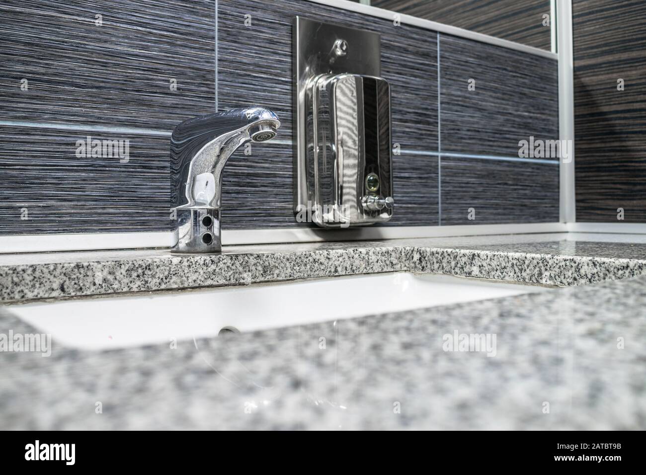 A modern washbasin with a container for liquid soap is in the public ...