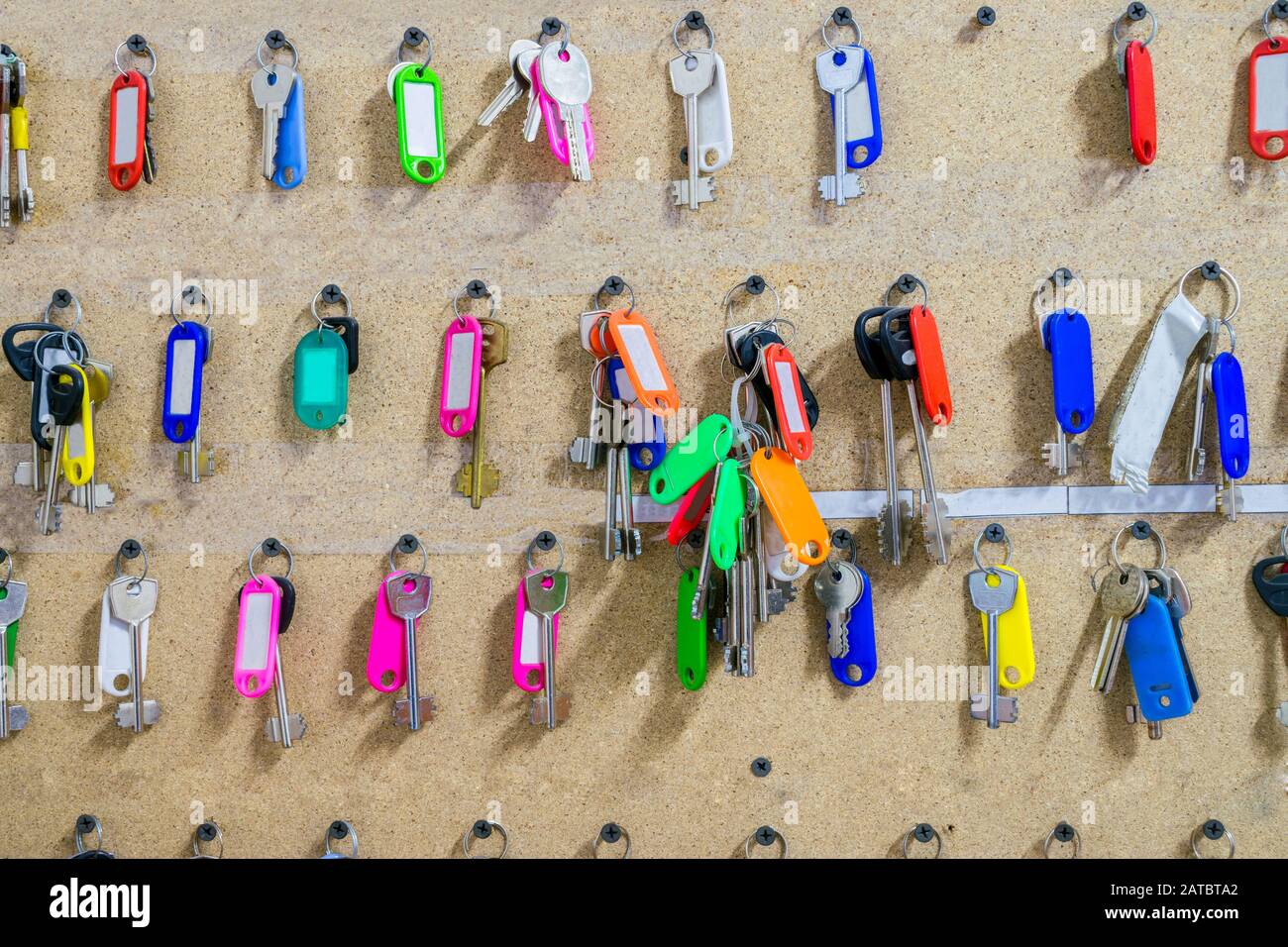 A board with lots of room keys hangs in the hostel. Many keys with ...