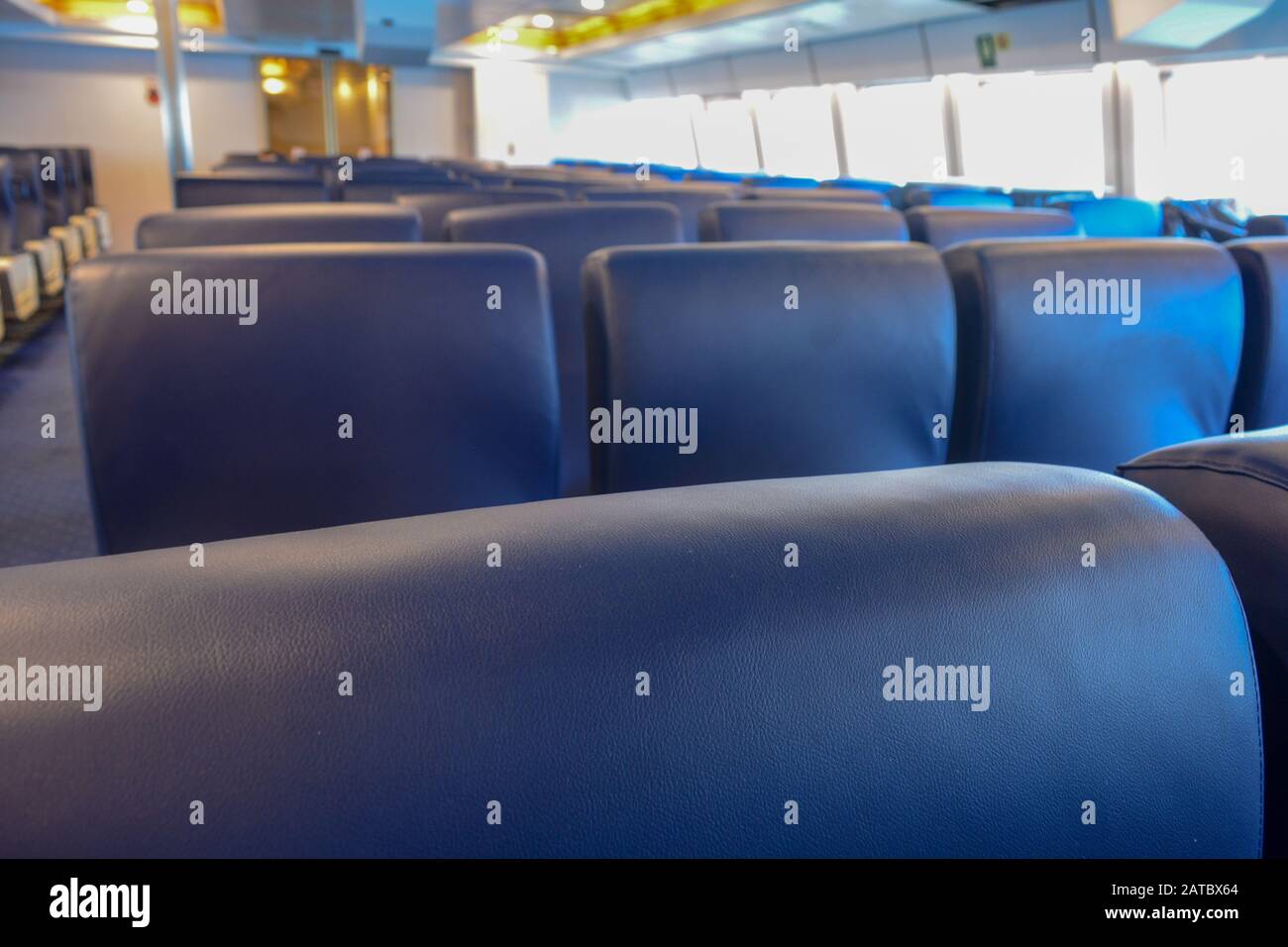 An elegant lounge inside a ferry. Rows of comfortable empty blue seats ...
