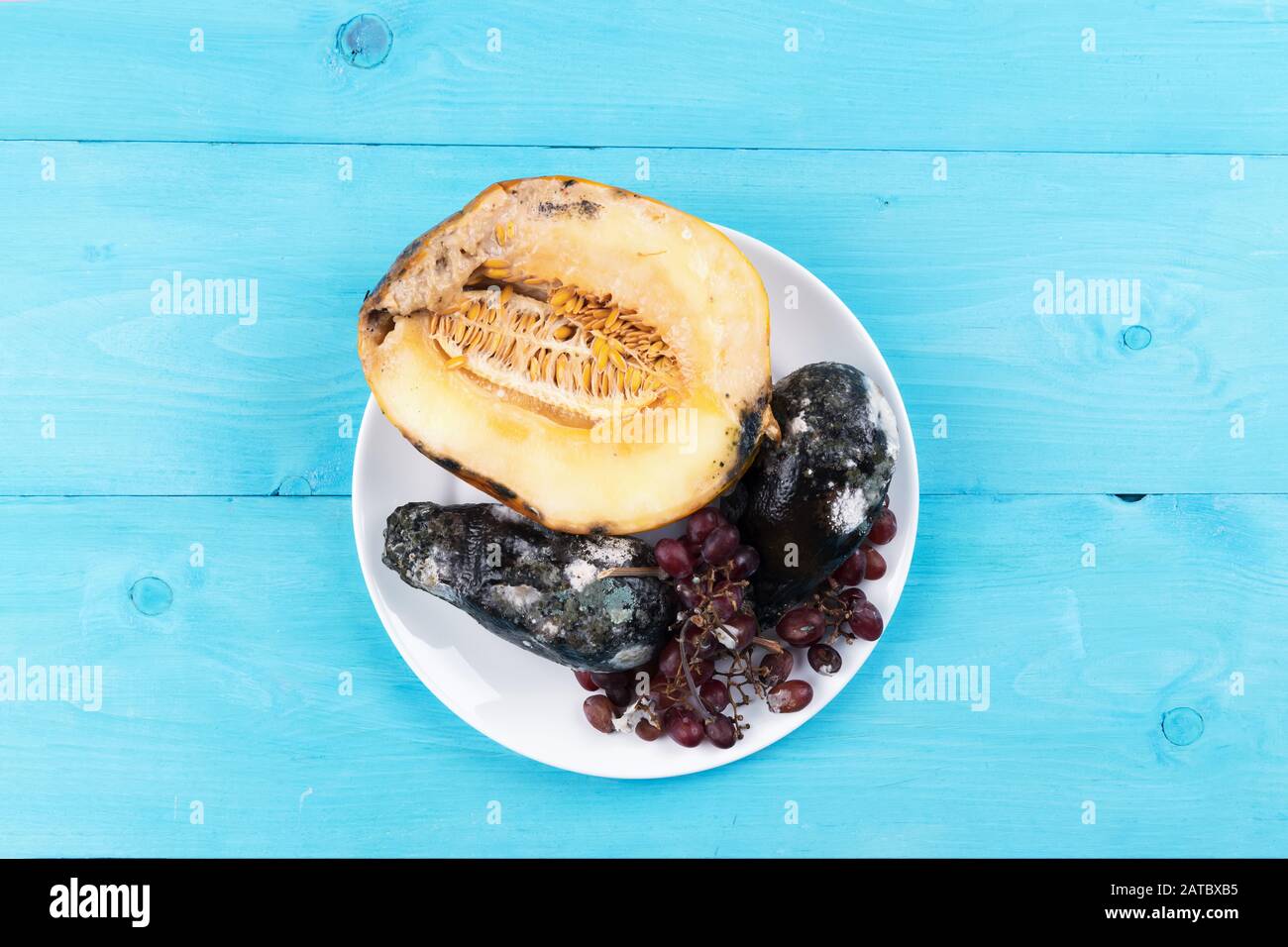 Moldy melon, grapes and avocados on a plate, concept of stop wasting ...