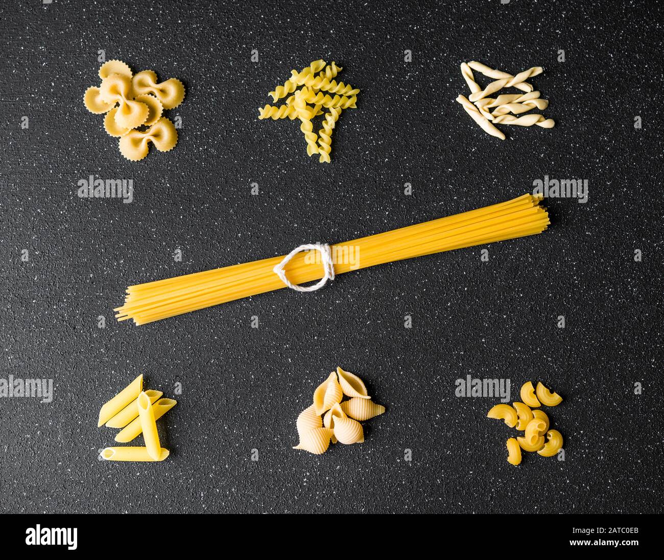 Assortment of different dry pasta types against black background, top ...