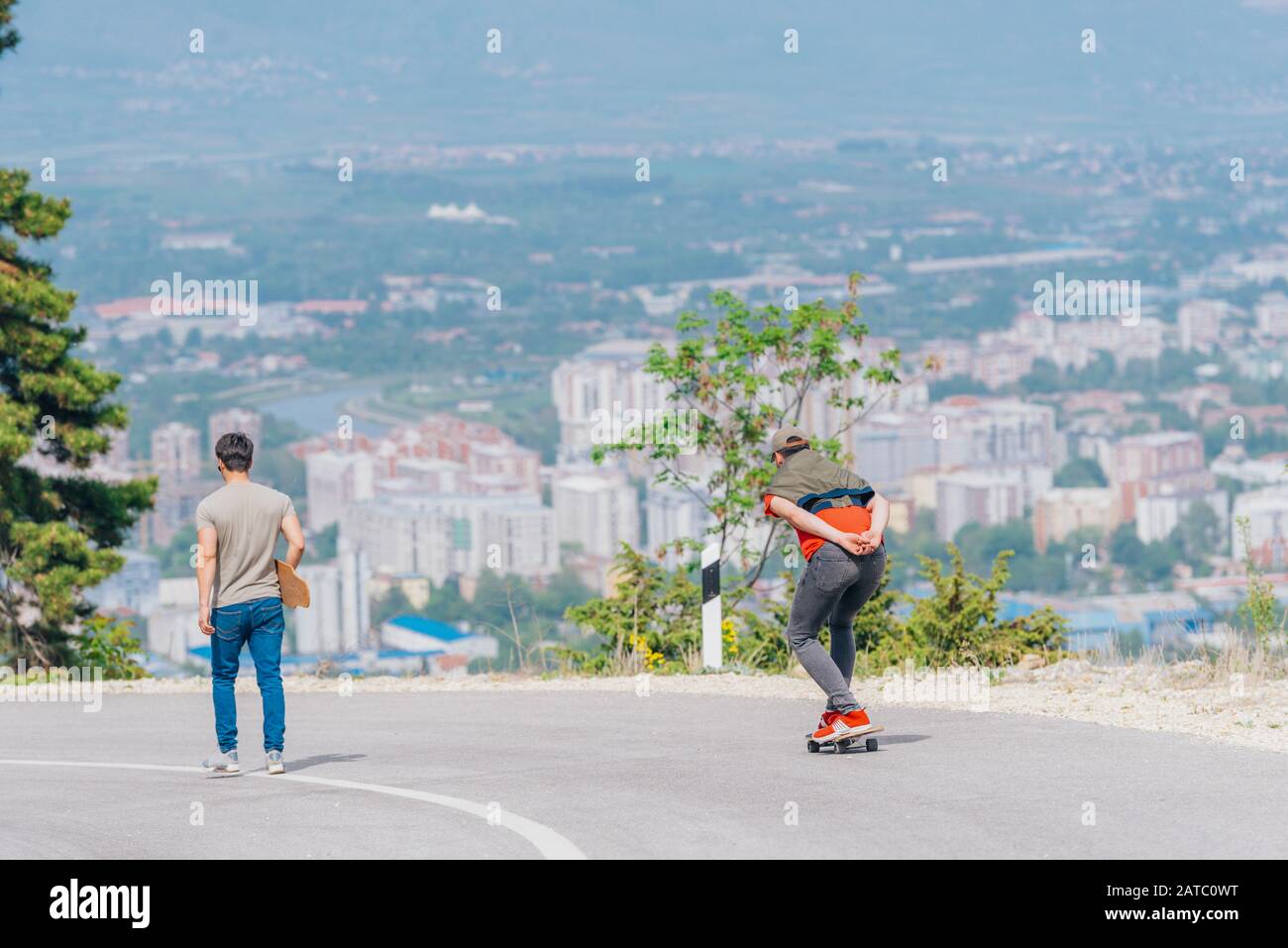 Tall athlete riding his longboard fast and steady downhill while ...