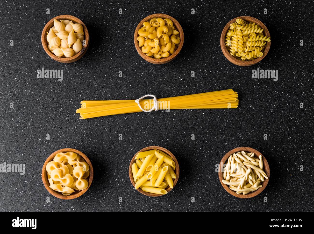 Assortment of different dry pasta types against black background, top ...