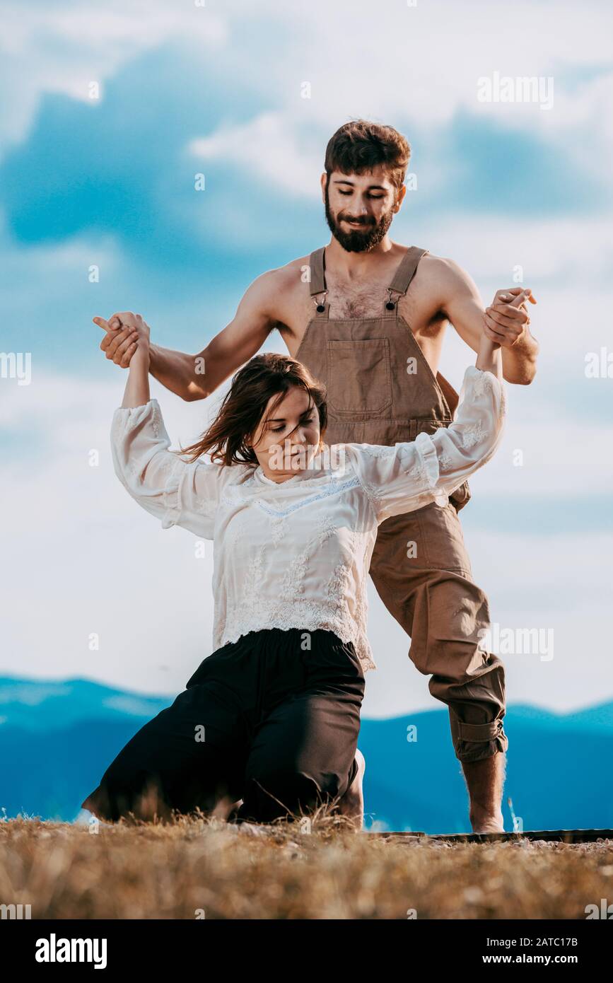 Romantic young loving couple dancing outdoors under blue sky at ...