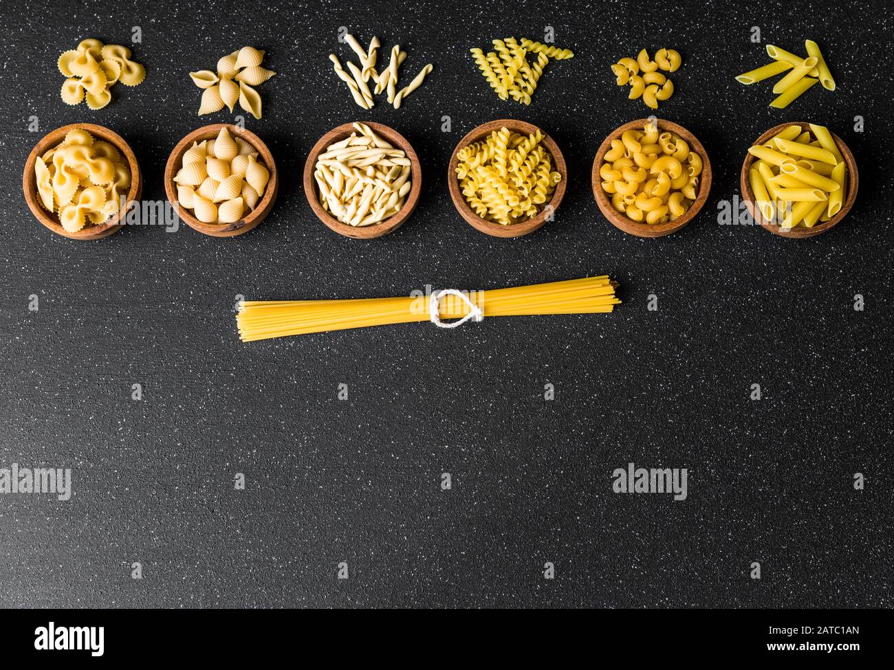 Assortment of different dry pasta types against black background, top ...