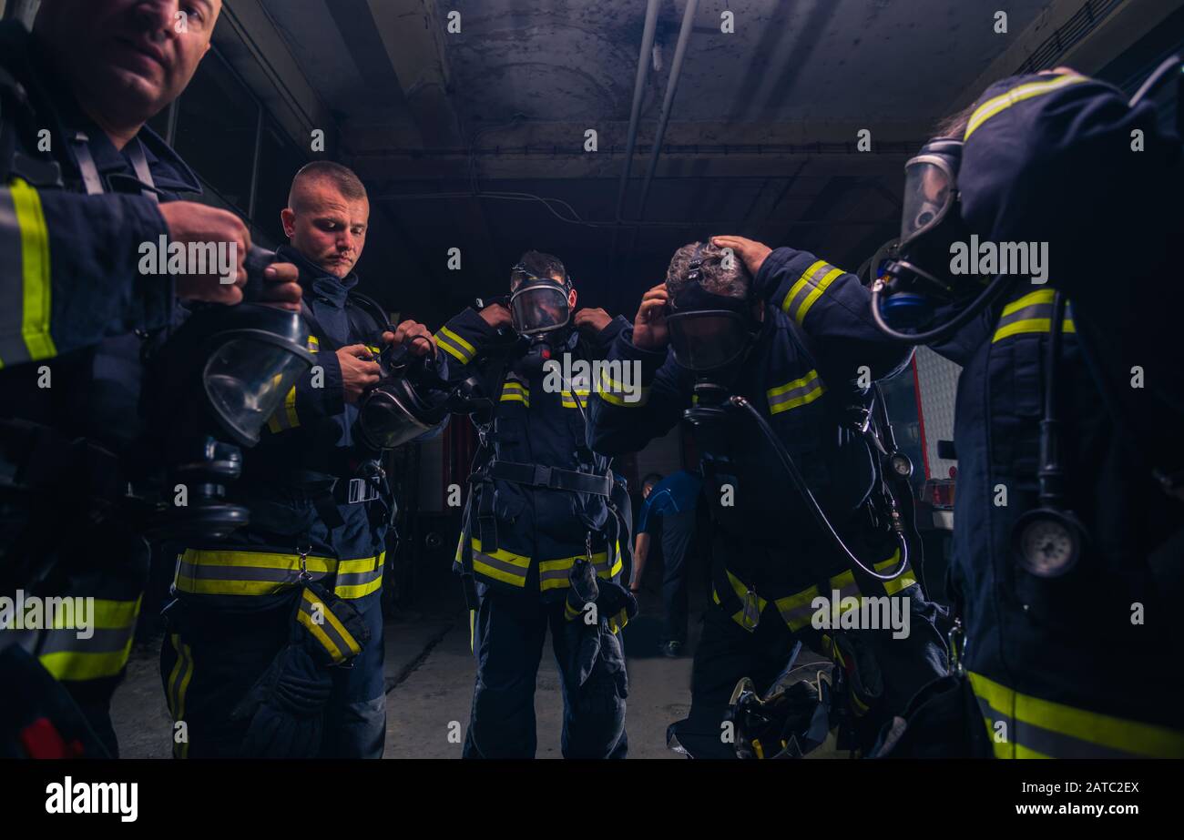 Group of firefighters standing inside the fire brigade wearing helmet ...