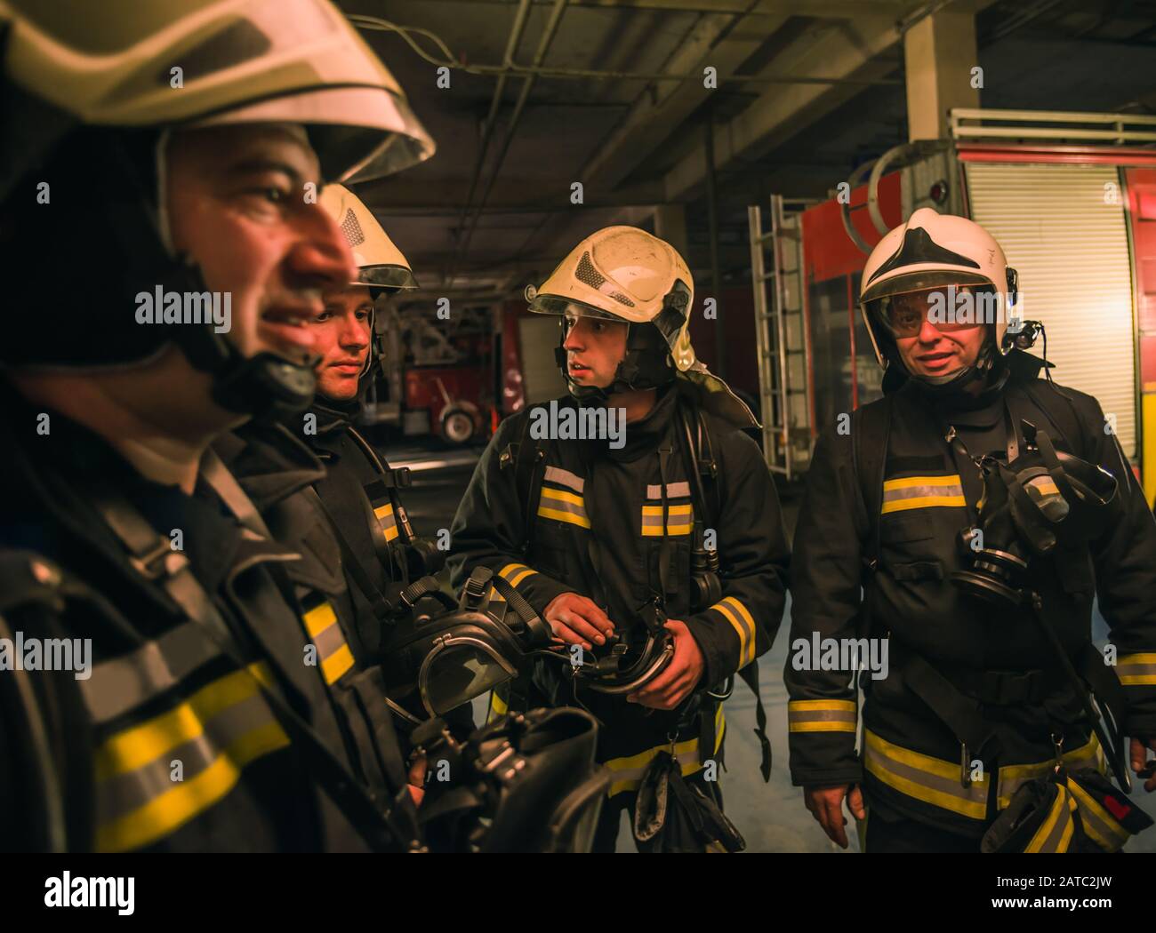 Group of firefighters with uniform inside the fire station preparing ...