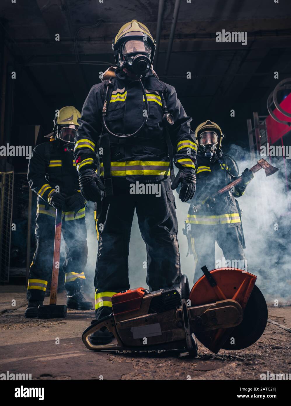 Group of three young fireman posing inside the fire department with ...
