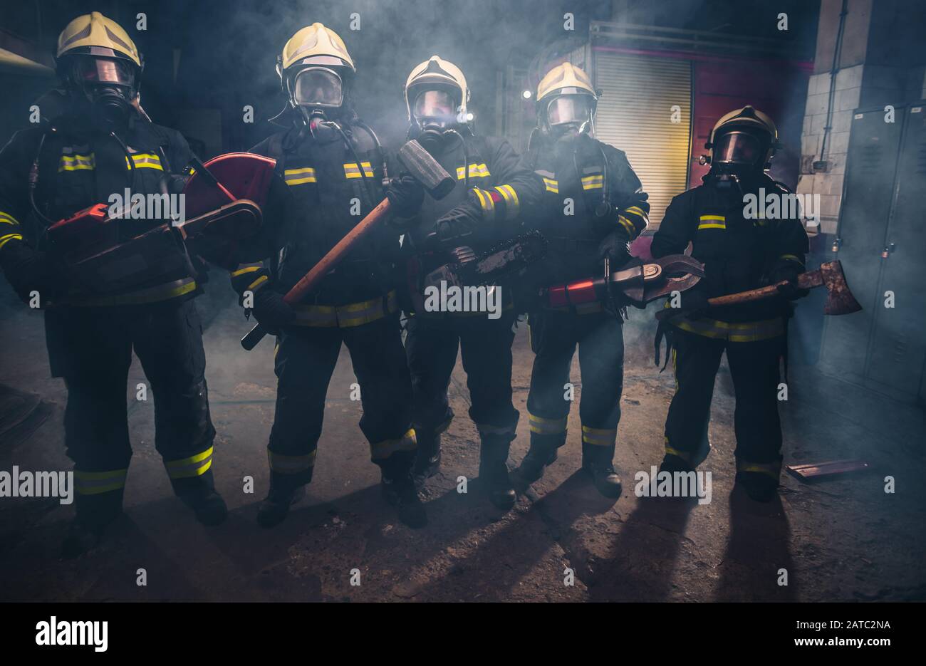 Group of firefighters with chainsaw and sledge hammer practicing in the ...