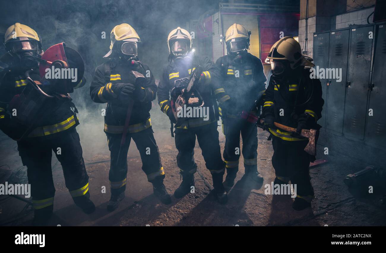 Group of firefighters with chainsaw and sledge hammer practicing in the ...