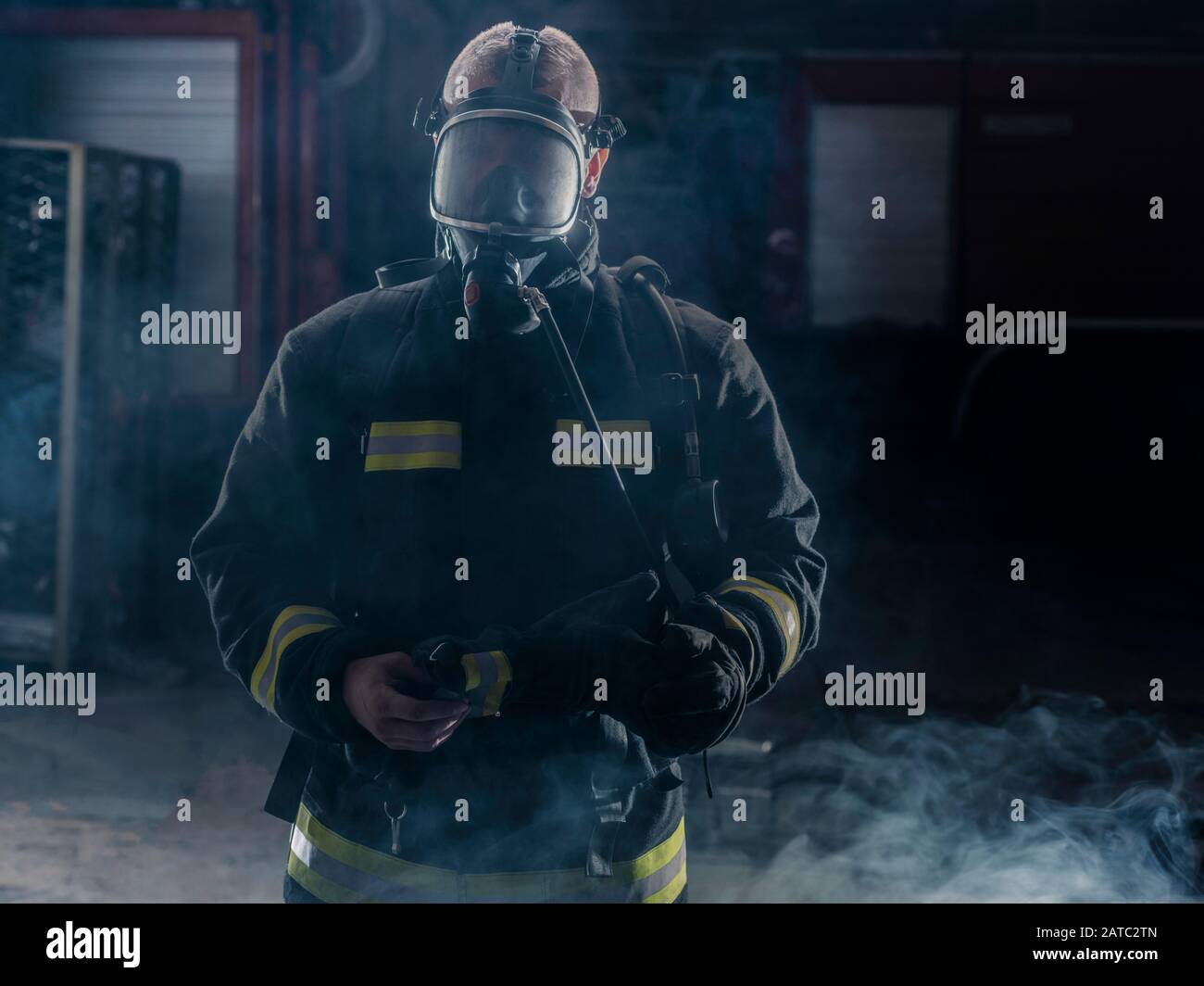 Portrait of a fireman wearing firefighter turnouts and helmet. Dark ...