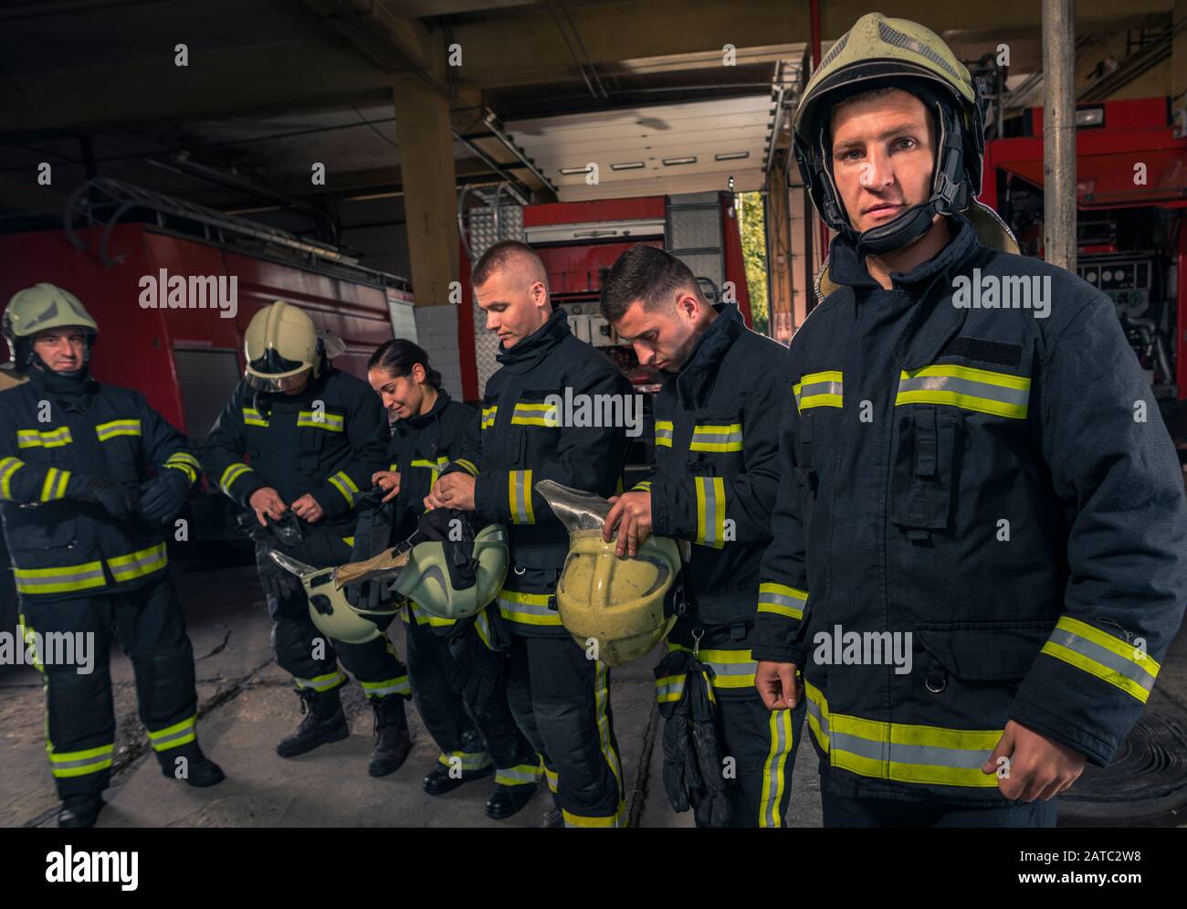 Firemen preparing for emergency service. Firefighters putting on gloves ...