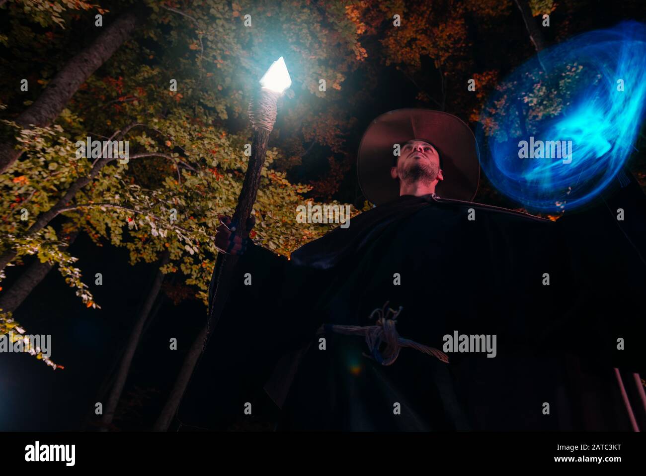 Wizard (mage) casting a spell with his magical staff while standing in ...