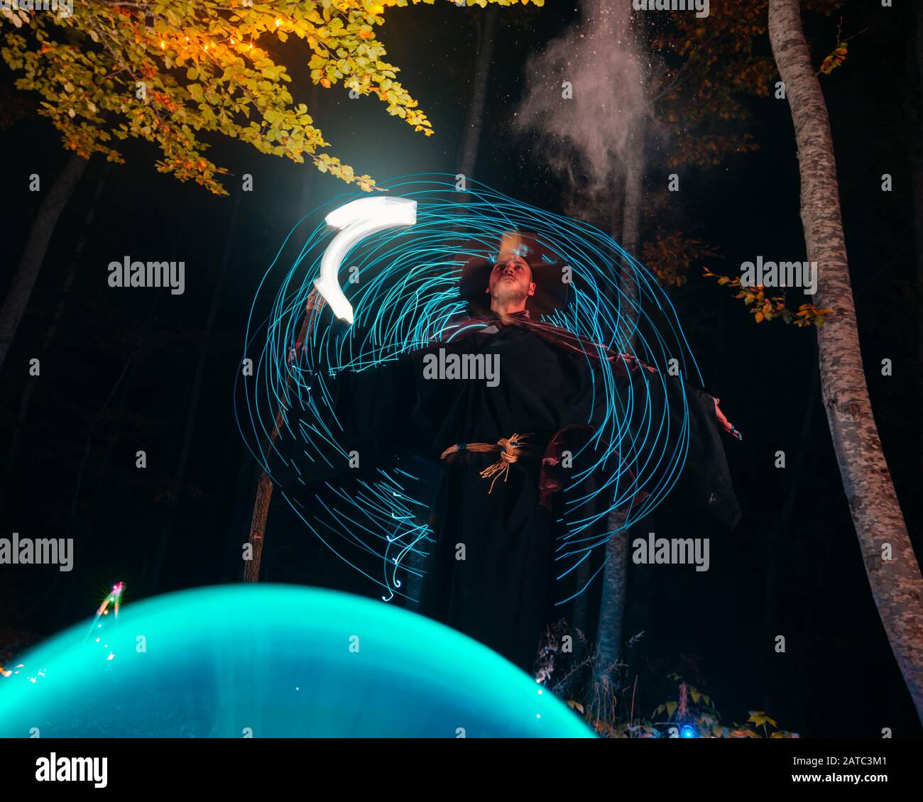 Sorcerer (magician) casting a spell while standing in the magical woods ...