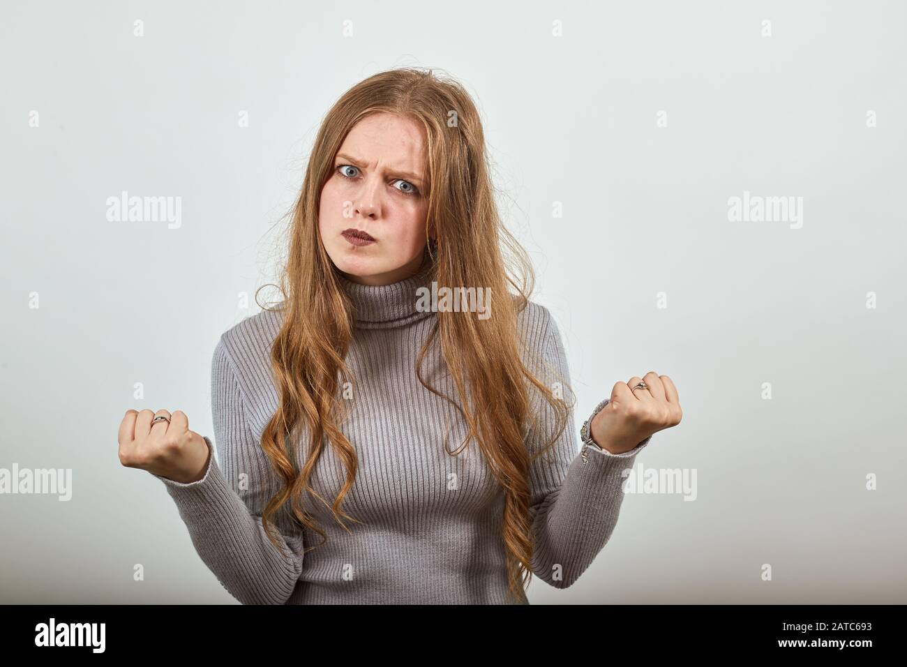 An angry irritated young woman with red hair is nervous looking at the ...