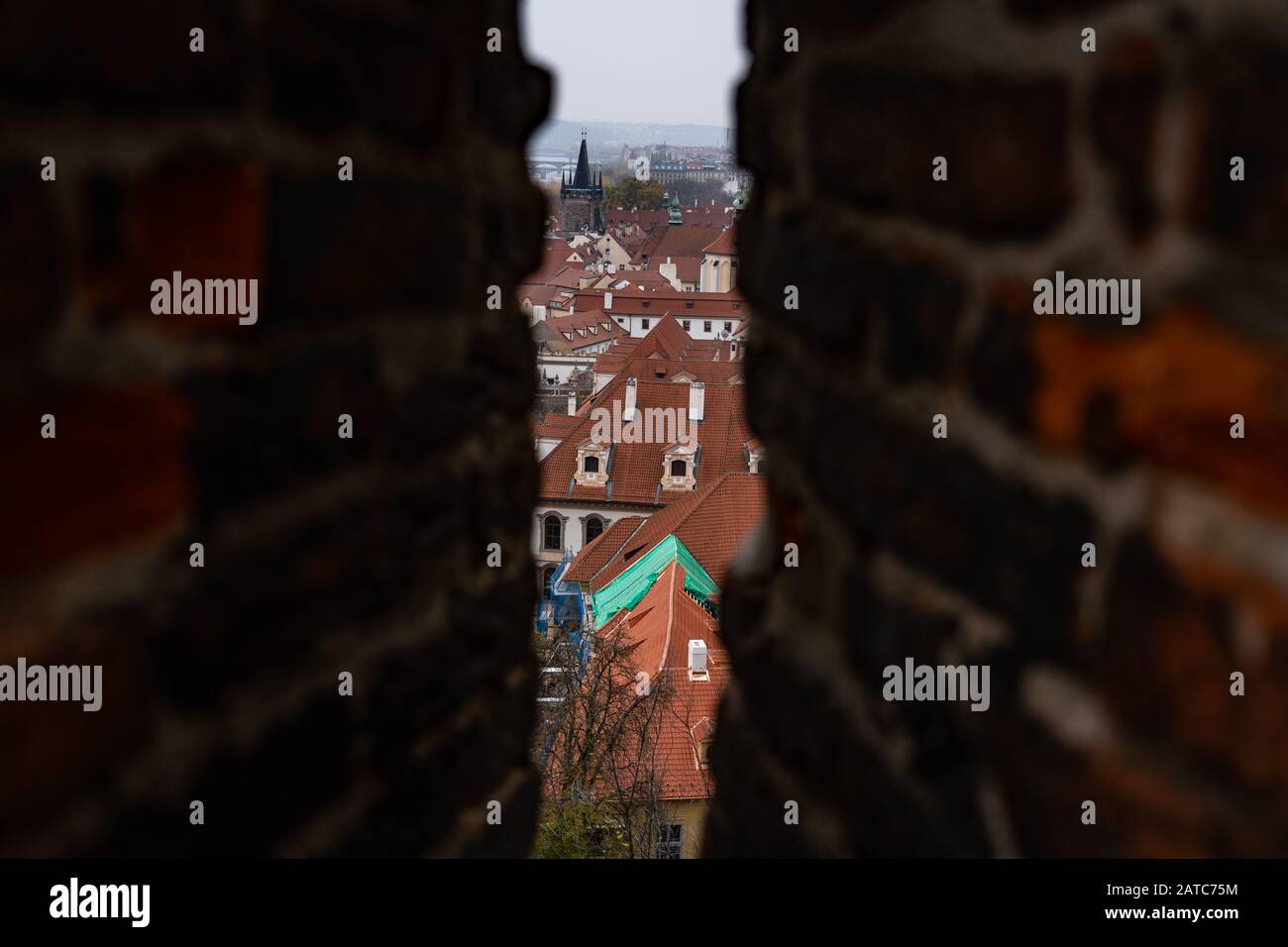 roof tops through a crevice in a wall, over the top of Prague in Czech ...