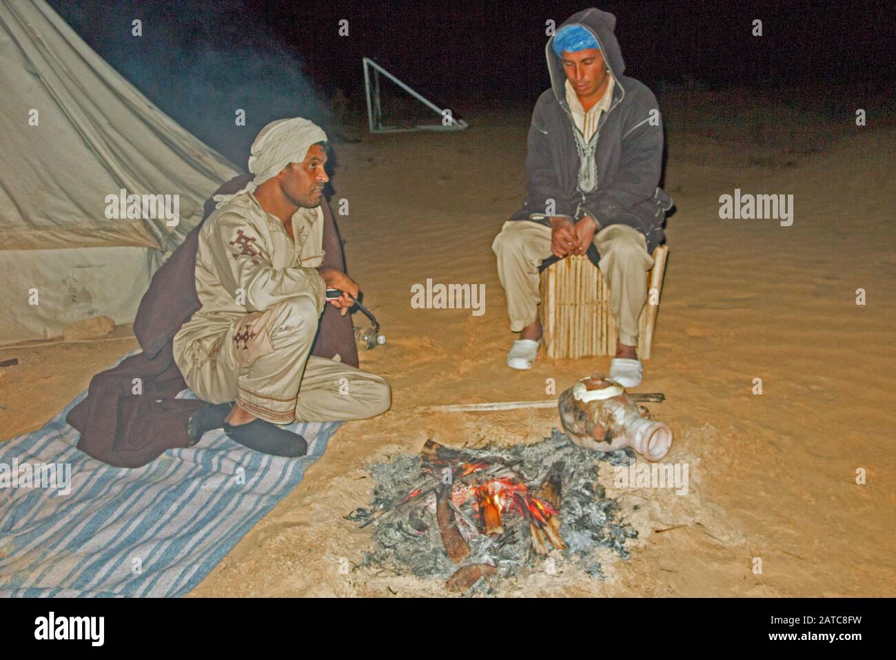 A traditional clay pot next to a charred campfire where food has been ...