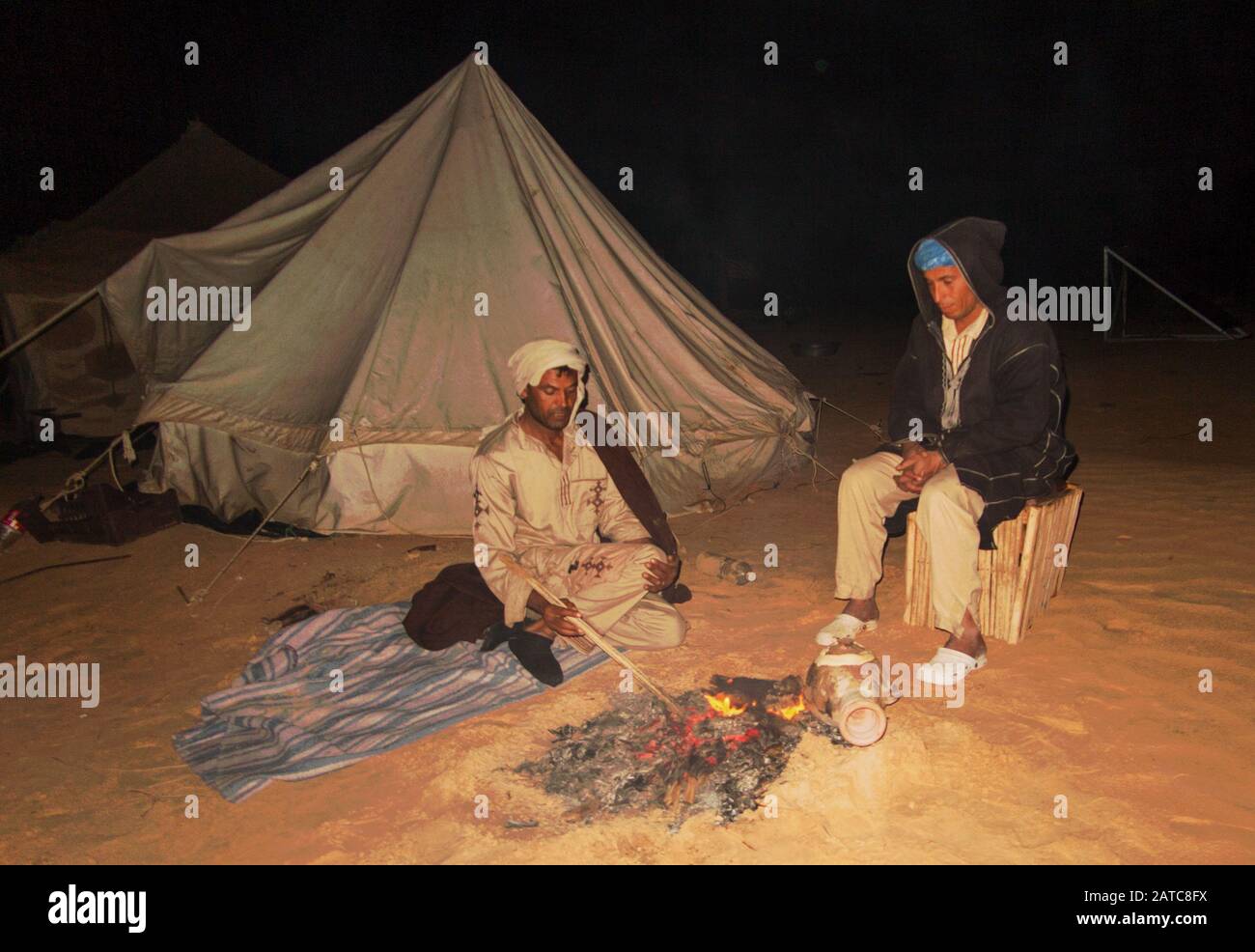 A traditional clay pot next to a charred campfire where food has been ...