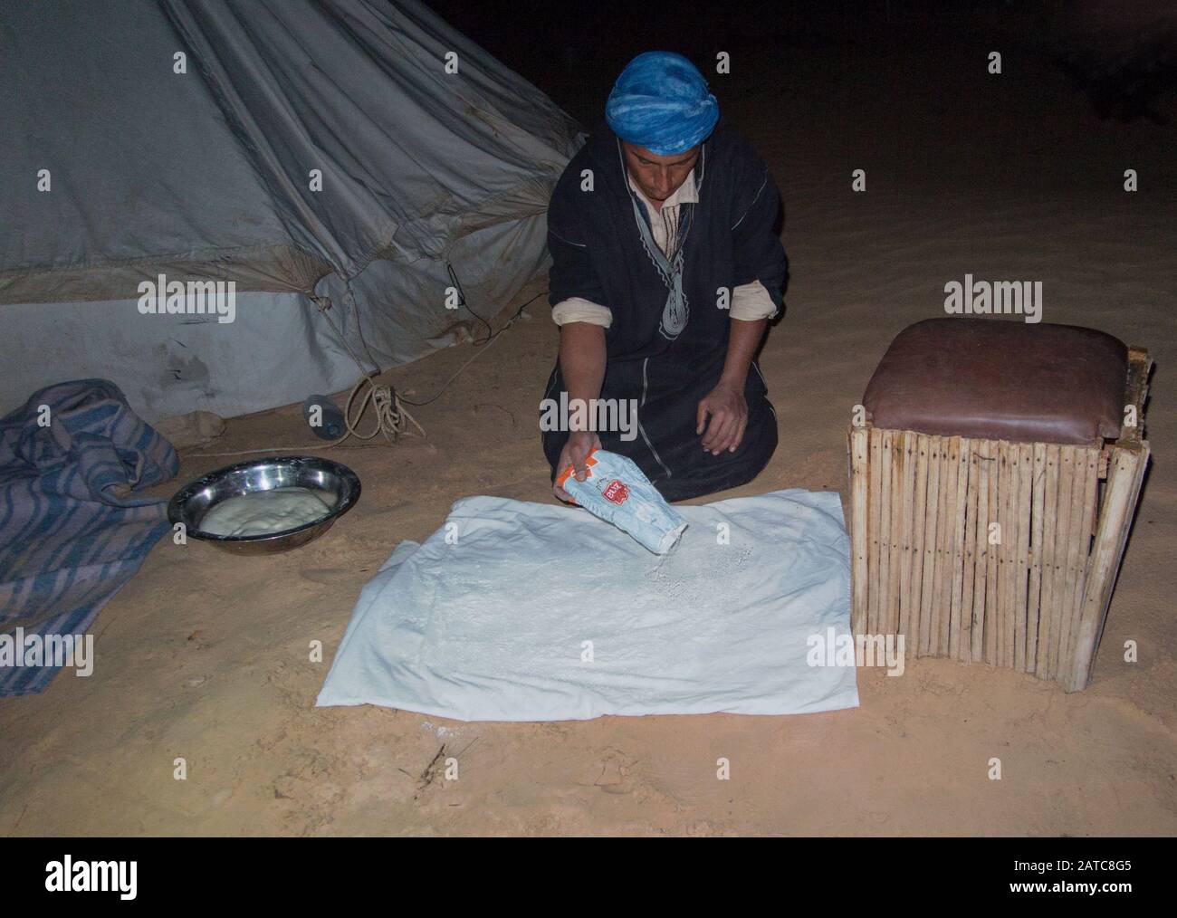 A man prepars to bake bread with charcoal and sand as has always been ...
