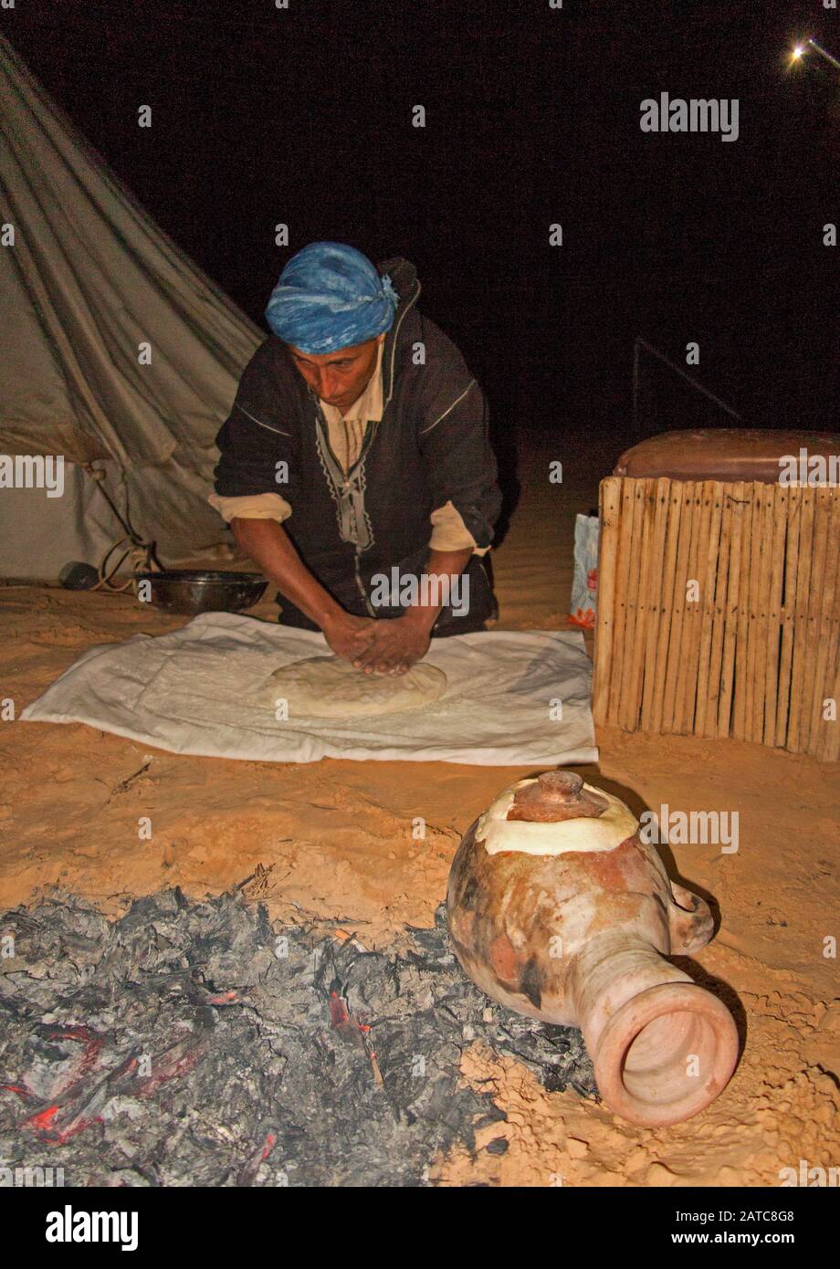 A traditional clay pot next to a charred campfire where food has been ...