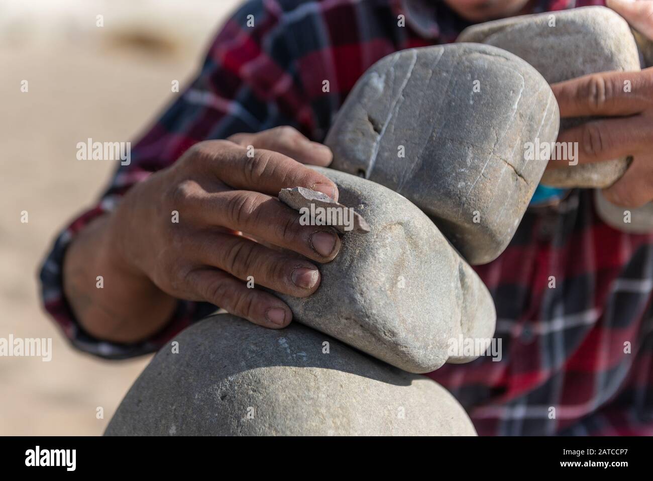 Rugged hands of a craftsman holding the a wedge stone in place for a ...