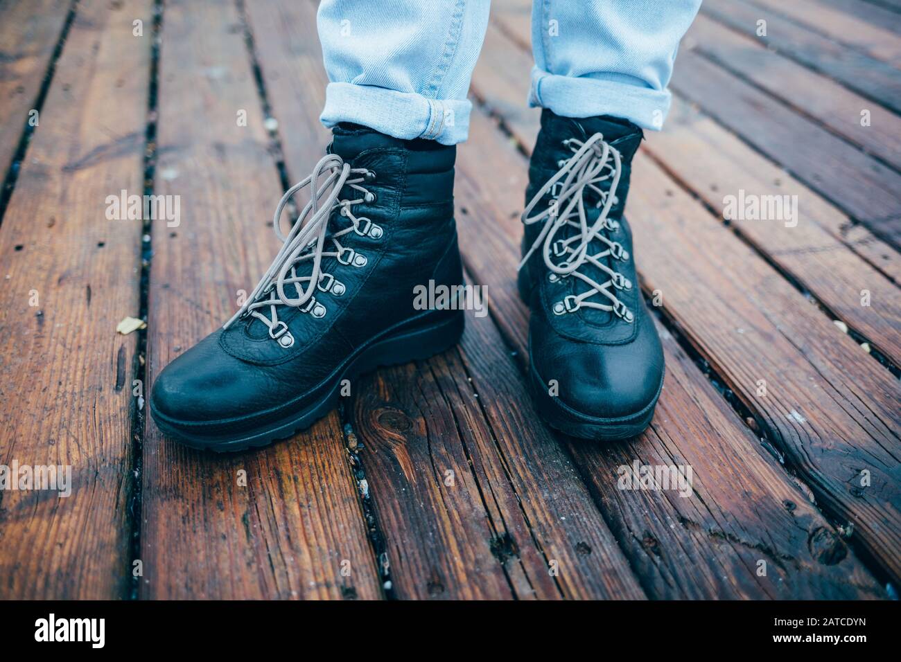 Close-up of woman's feets in jeans shod in rough laced boots standing ...