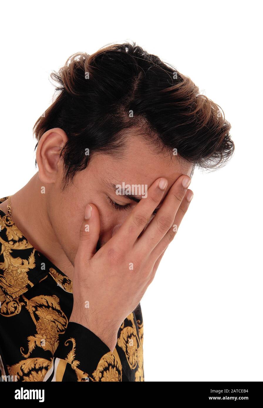 A young sad looking man standing in profile with his hand over his face ...