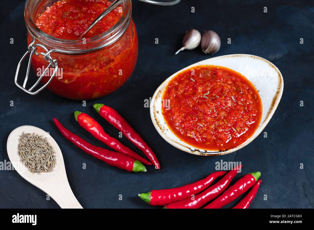 Hot chili pepper sauce paste harissa. Adjika on a blue background ...
