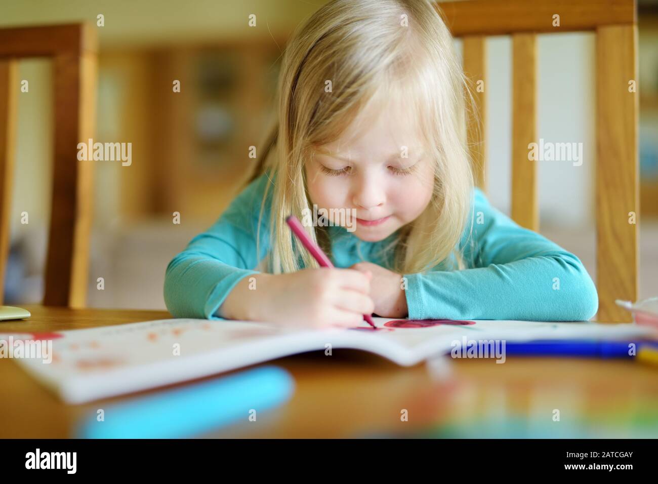 Cute little girl drawing with colorful pencils at a daycare. Creative ...