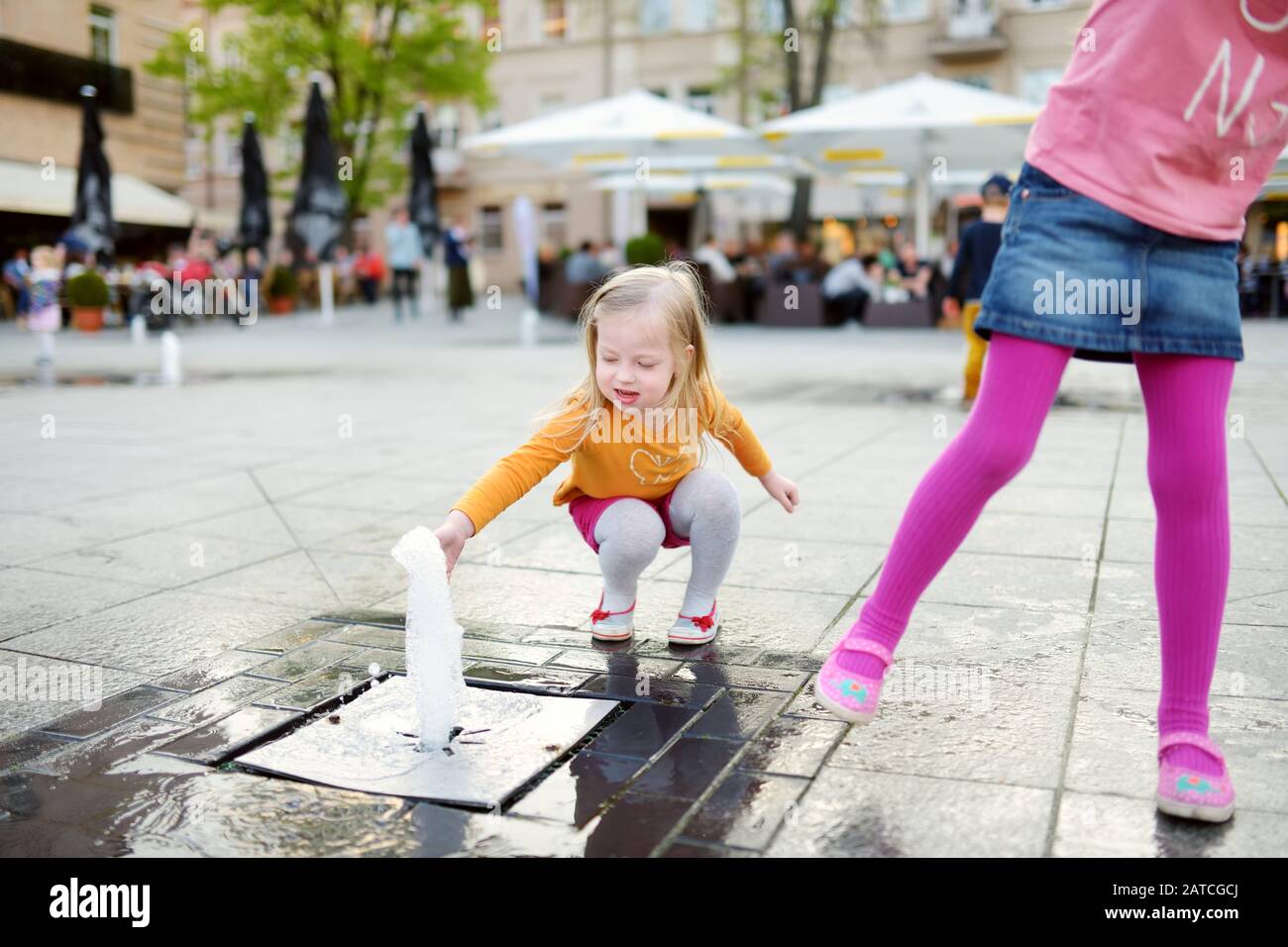 Cute young sisters playing in city fountains. Children having fun with ...