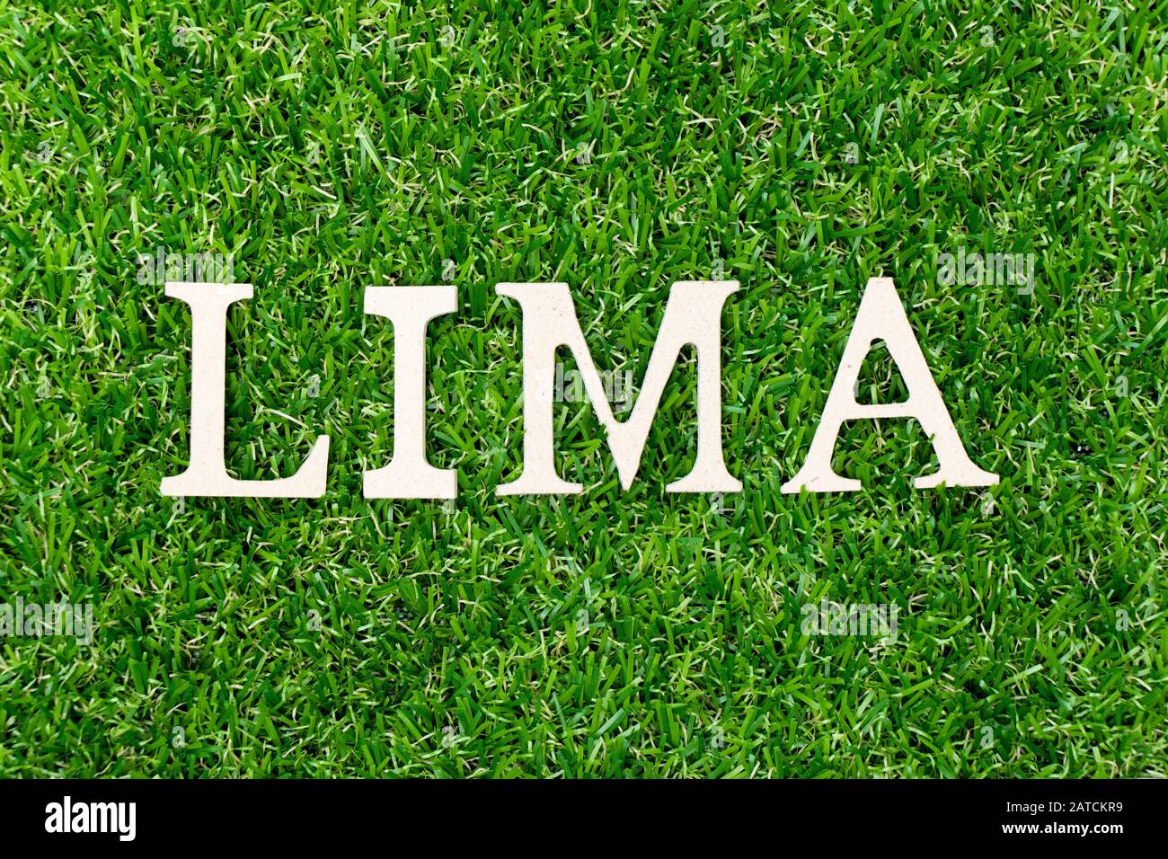 Wood letter in word Lima on green grass background Stock Photo - Alamy