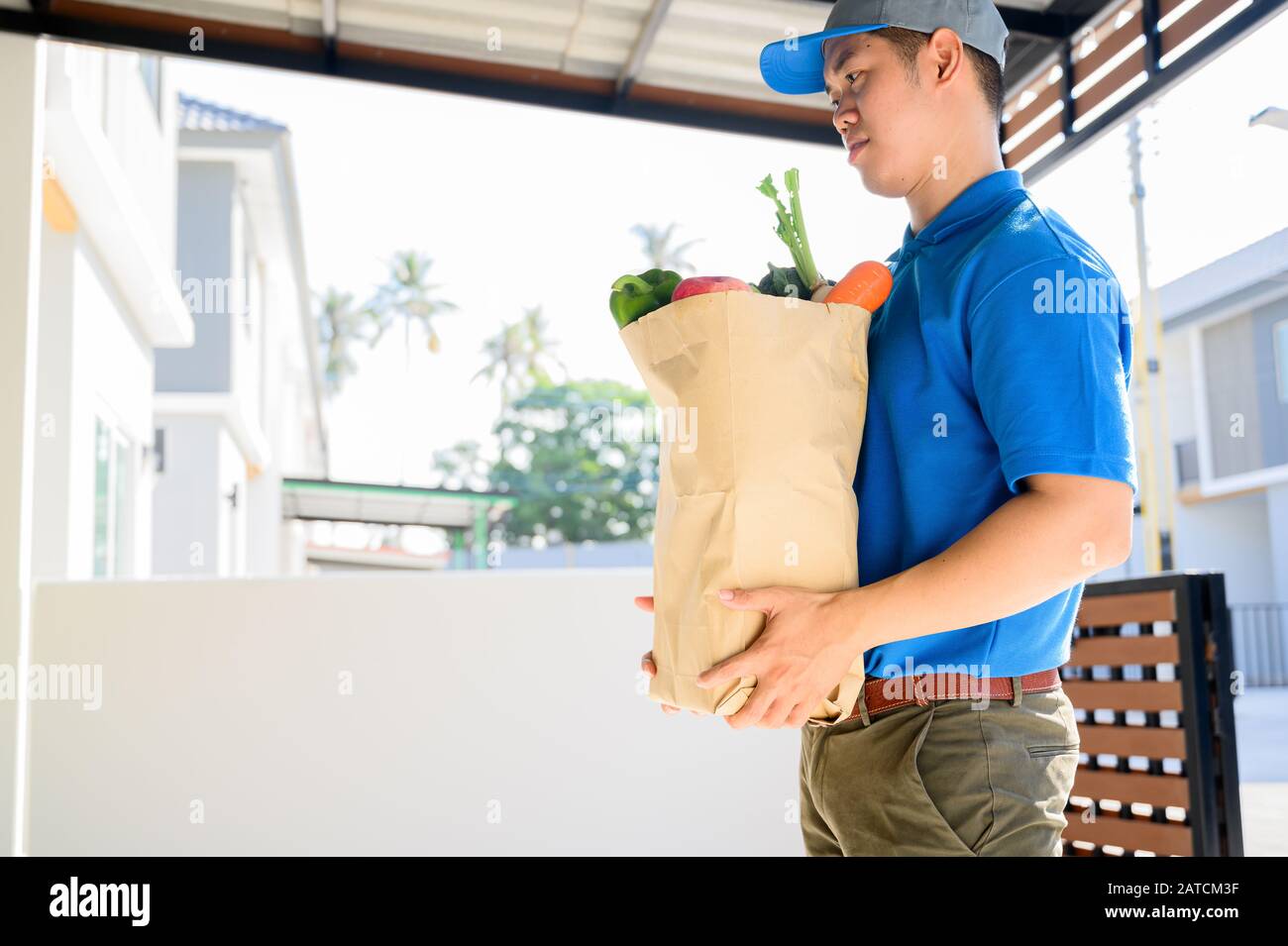 Food delivery service man in blue uniform. Thai deliveryman holding ...