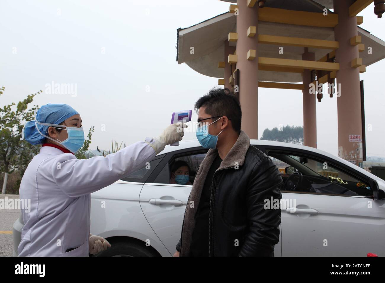 A Chinese medical worker checks the body temperature of a car driver ...