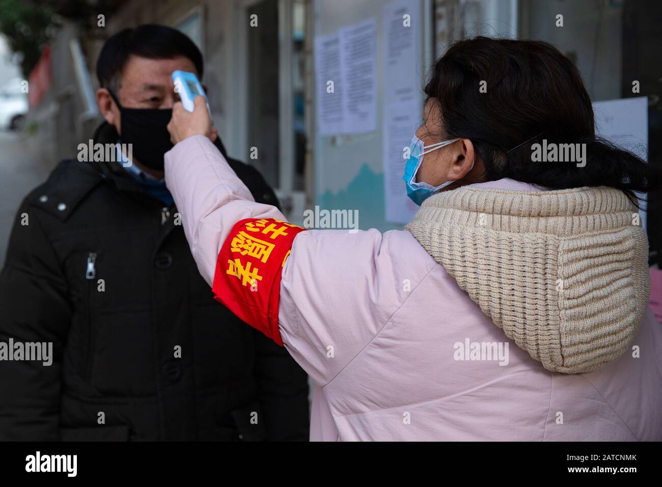 A Chinese community volunteer checks the body temperature of an ...